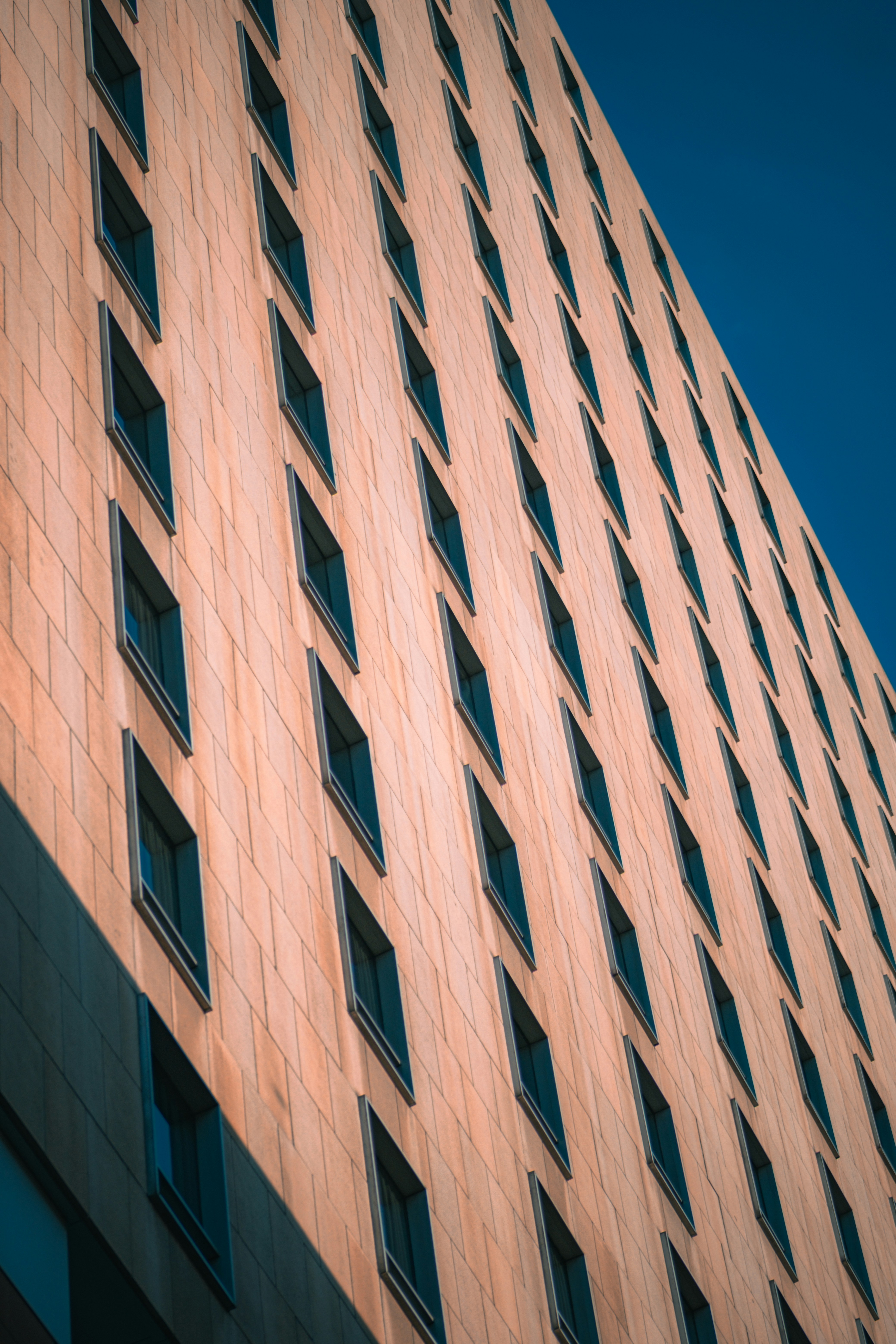 Diagonal Facade: Sunlit Brick Walls and Repeating Windows