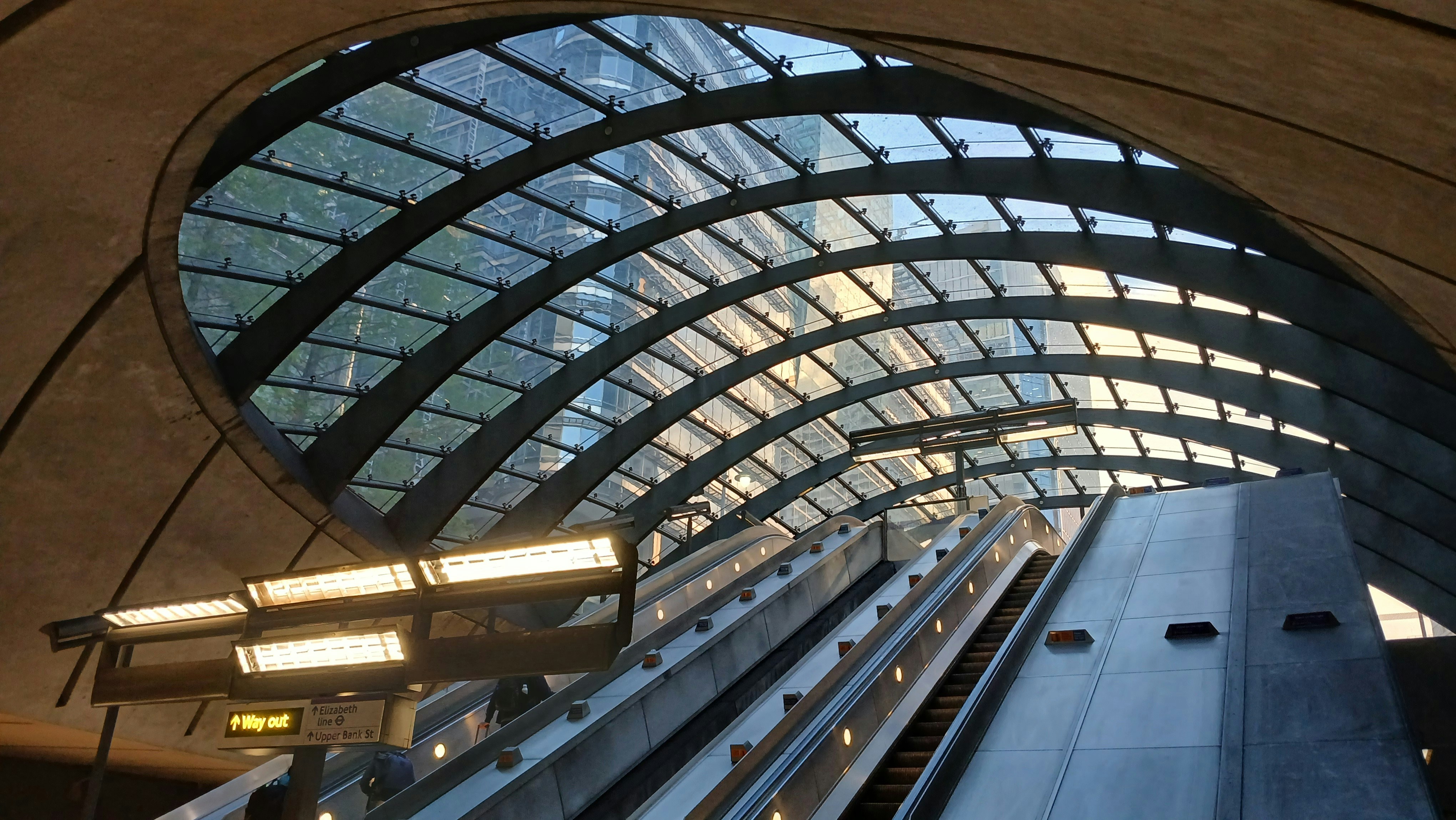 Curved Glass Roof Overhead: A Subway Station's Escalator Corridor