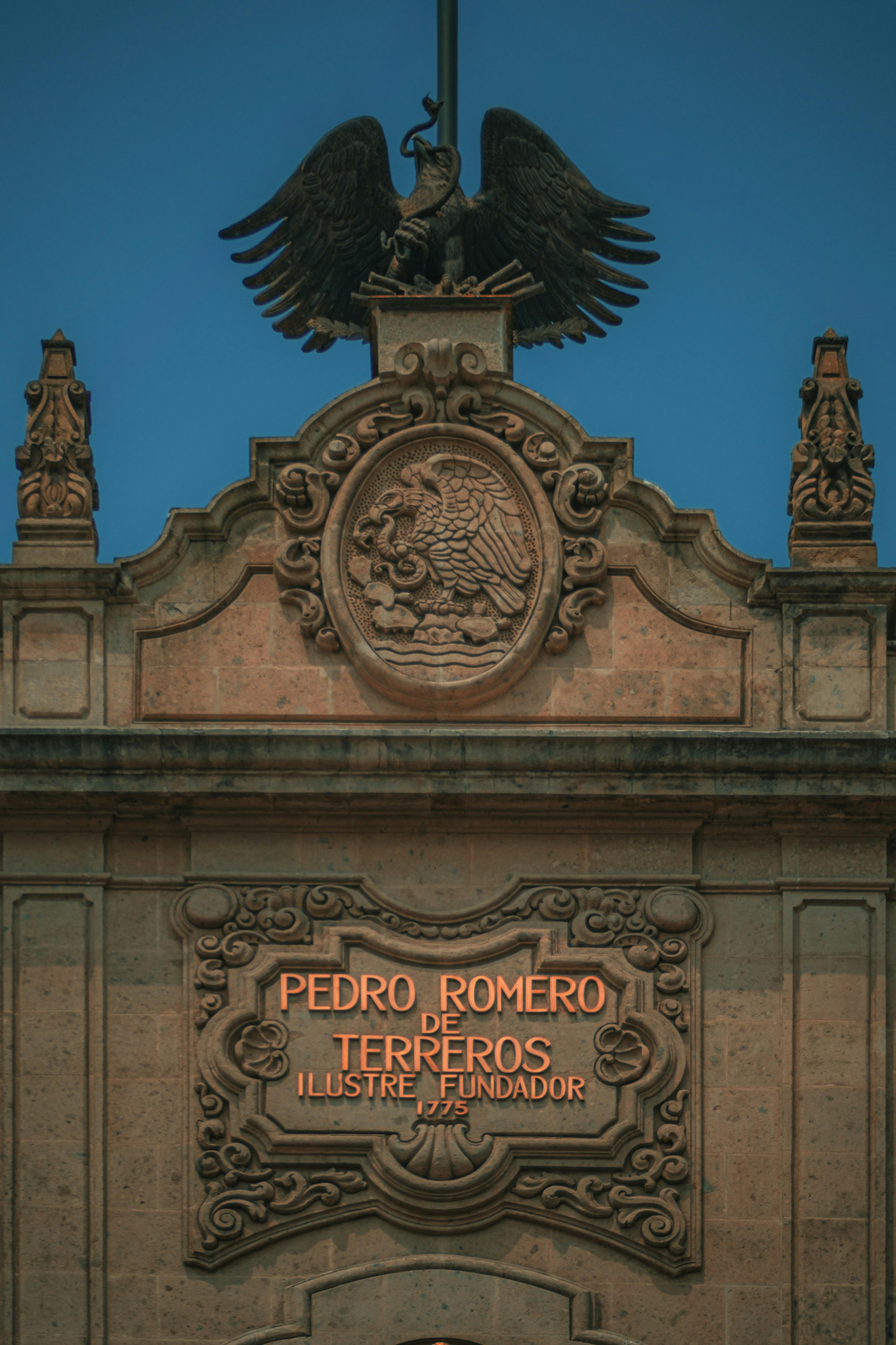 Ornate Plaza Crest: Eagle Mantled Above a Historic Pediment