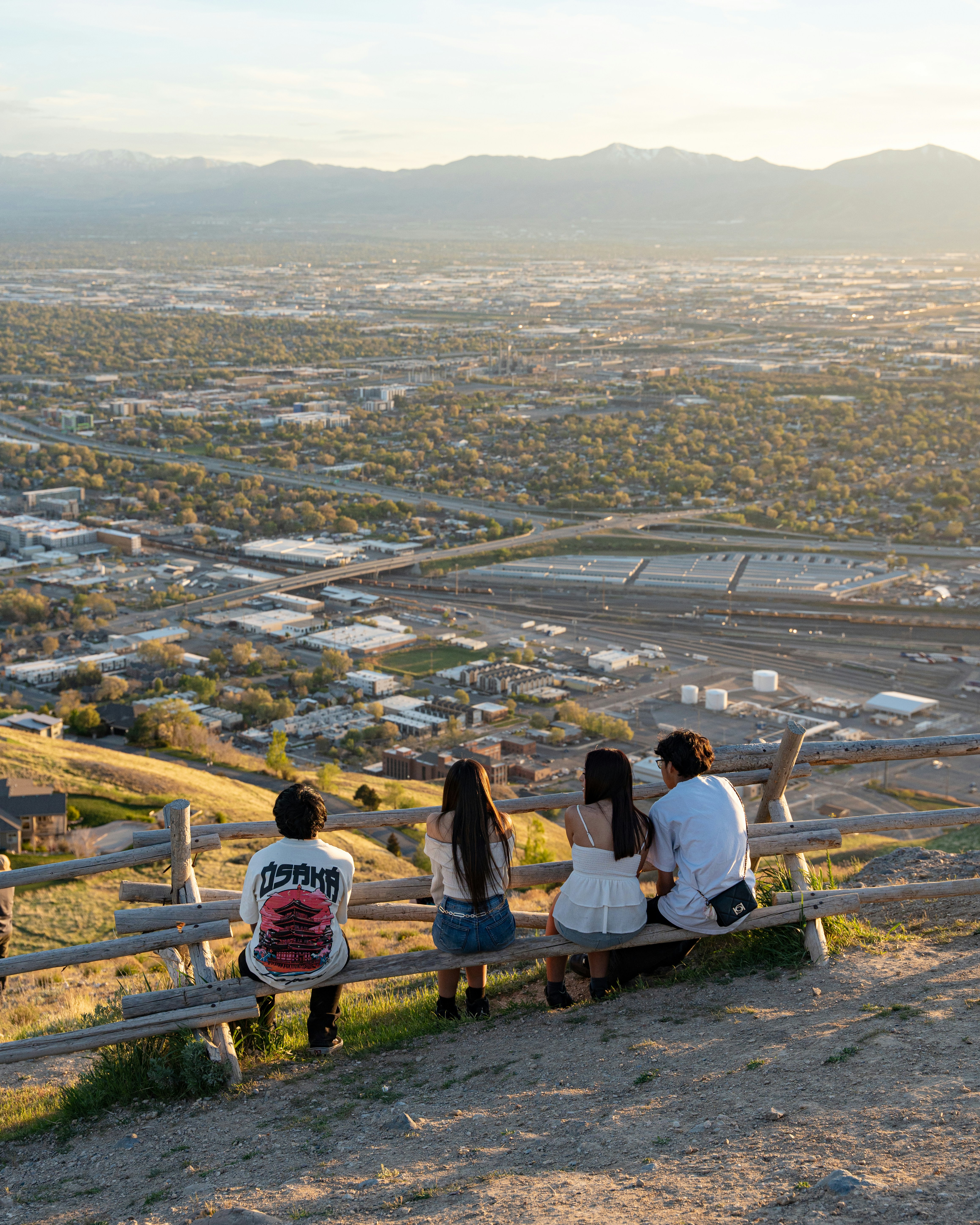 Friends atop a hill overlooking a sunlit valley and industrial expanse