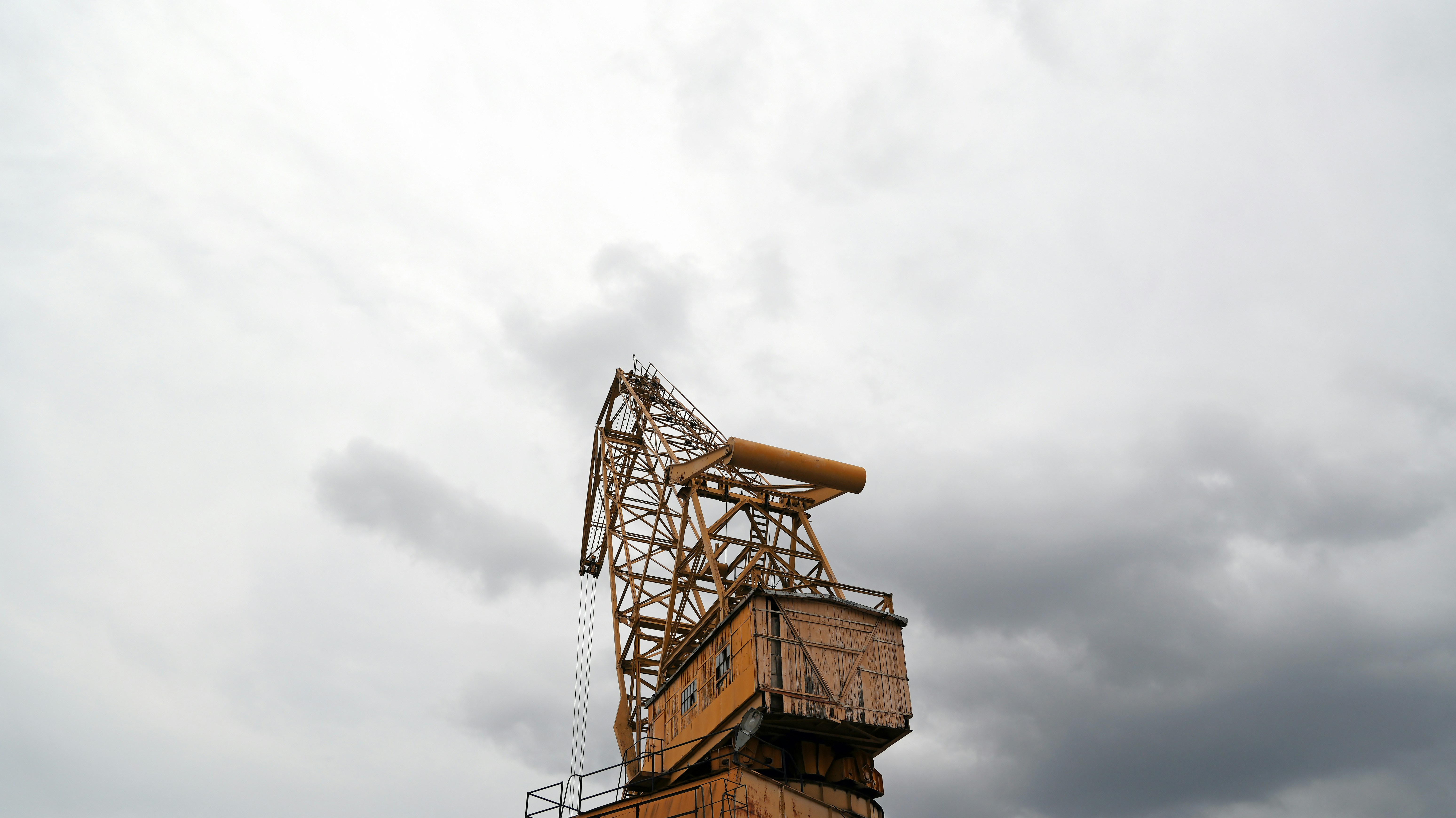 Industrial Sentinel: A Weathered Crane Reaching Toward Stormy Skies