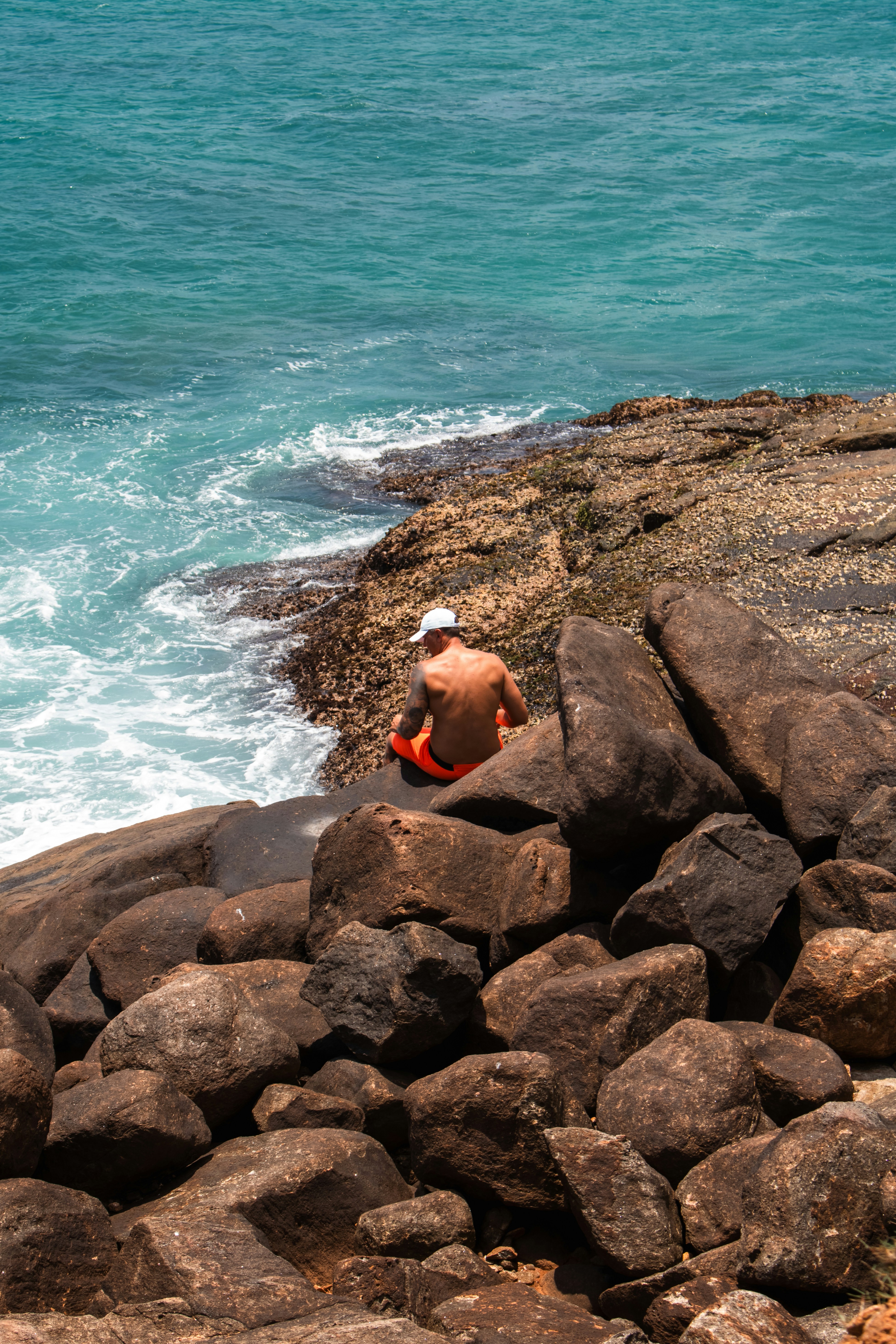 Solitary Figure on Ocean-Rimmed Boulders