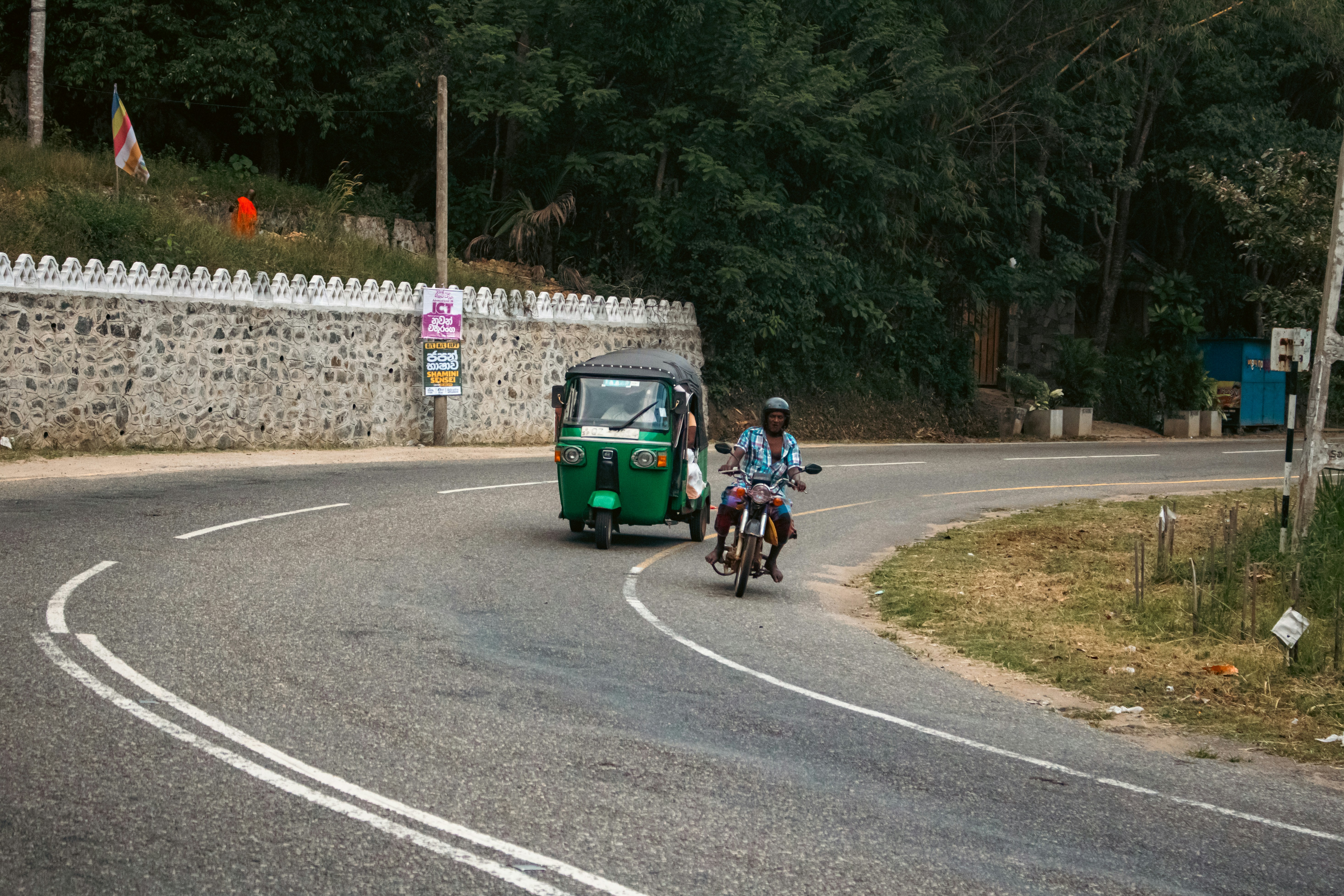 Green Auto and Rider on a Curving Road