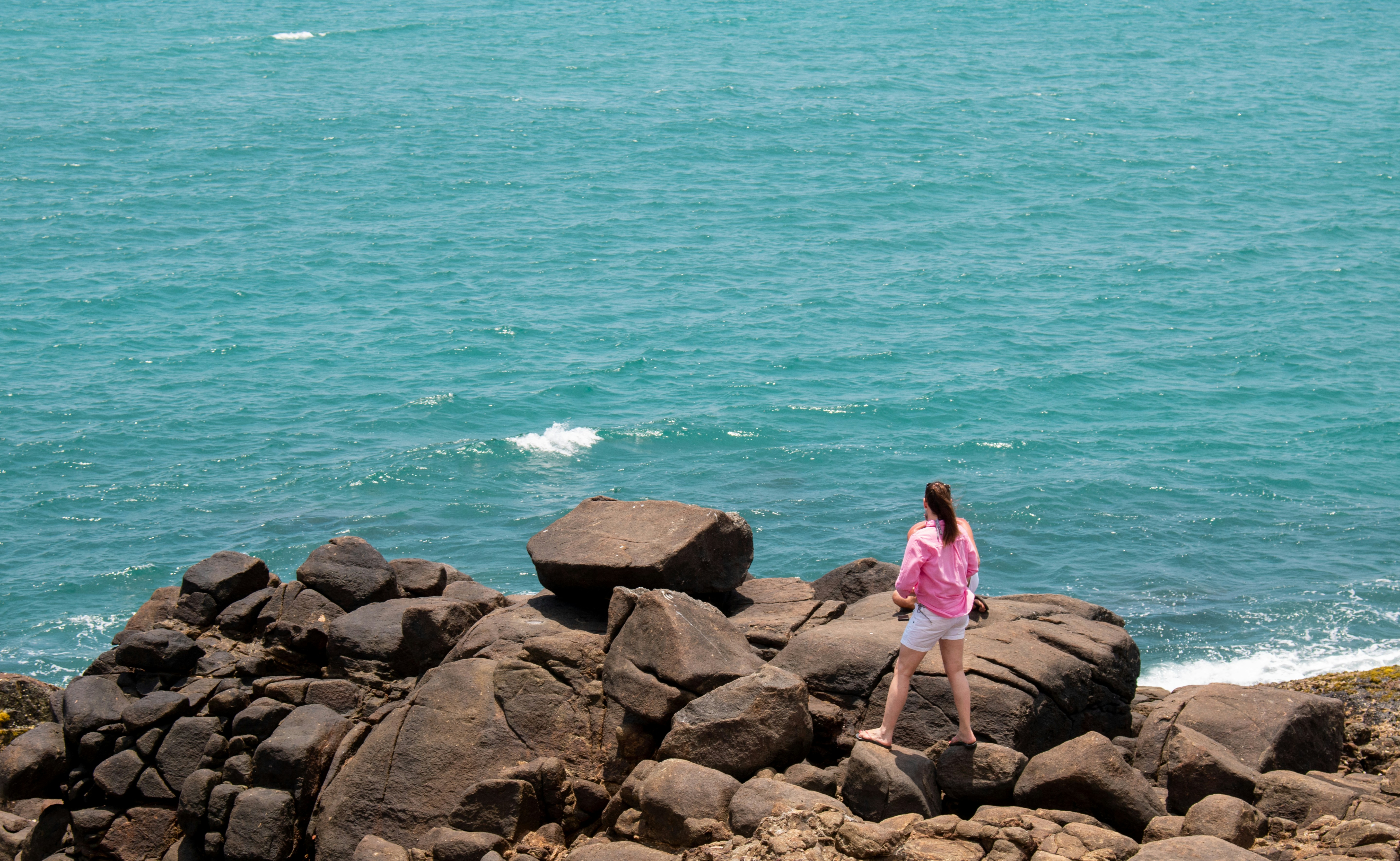 Rugged shoreline Rendezvous: A lone explorer on sunlit basalt