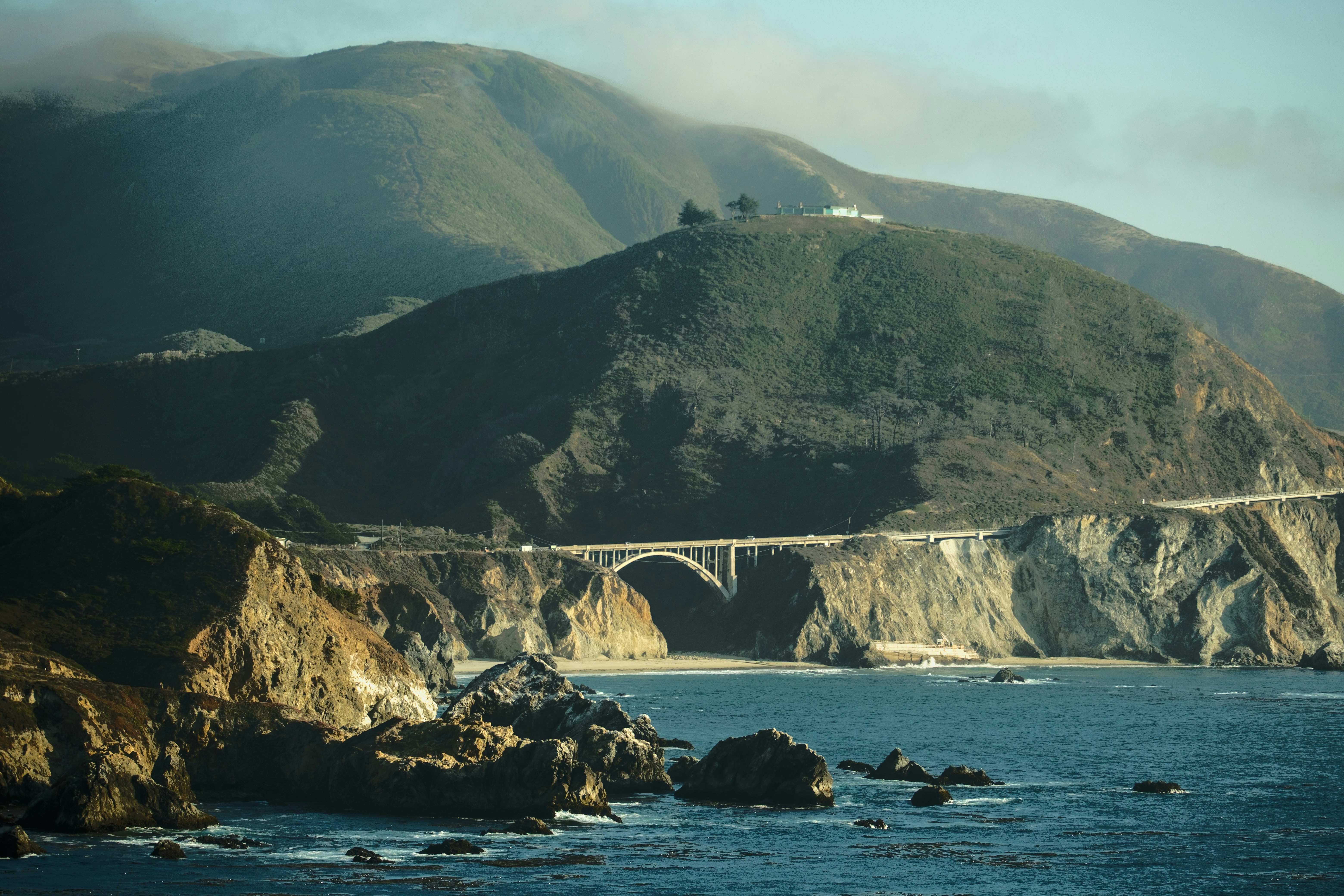 Coastal Ridge and Bridge: Sunlit Hills Over the Quiet Sea