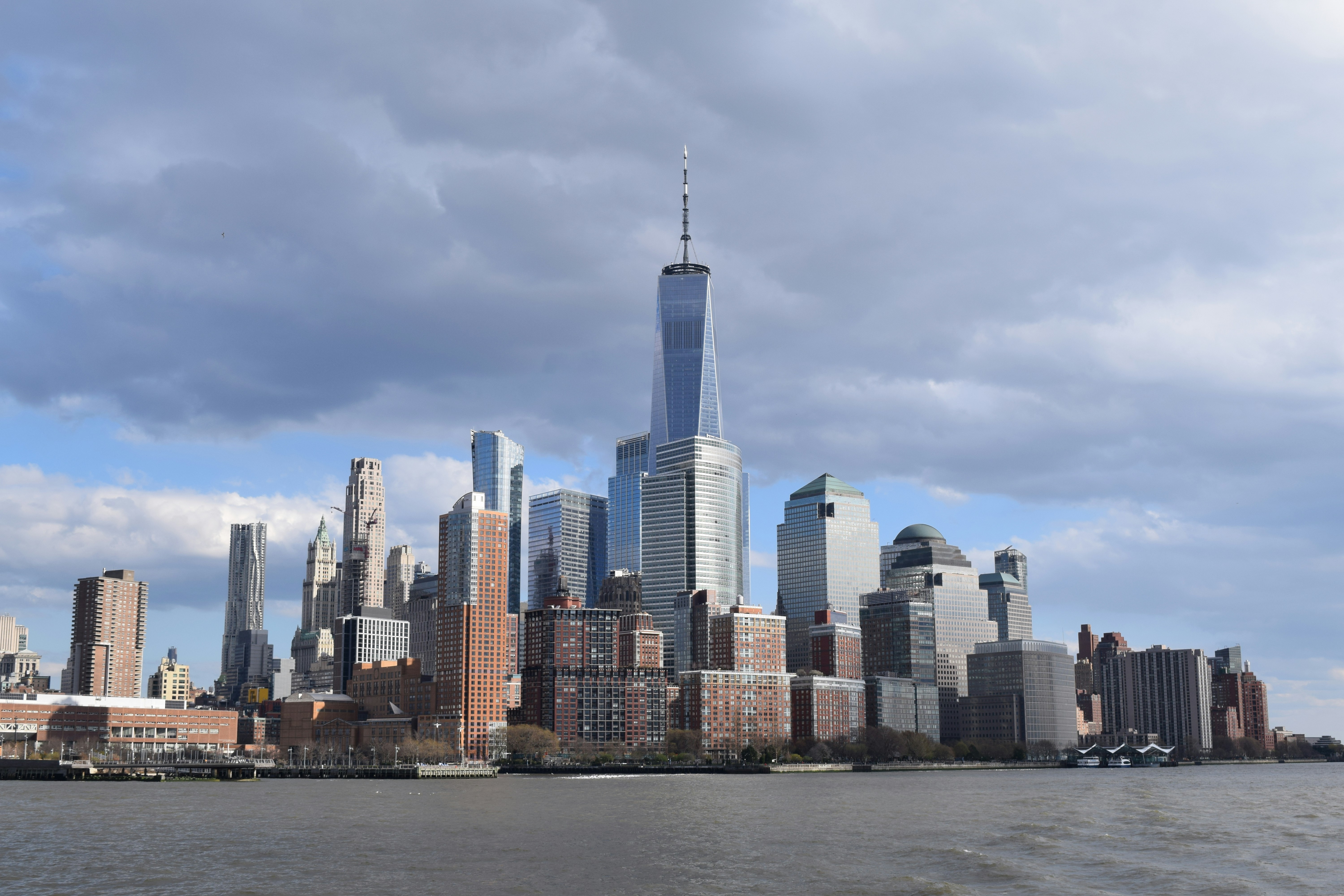 Skyline Arc: One World Tower Rising Over a Seawall of Brick and Glass