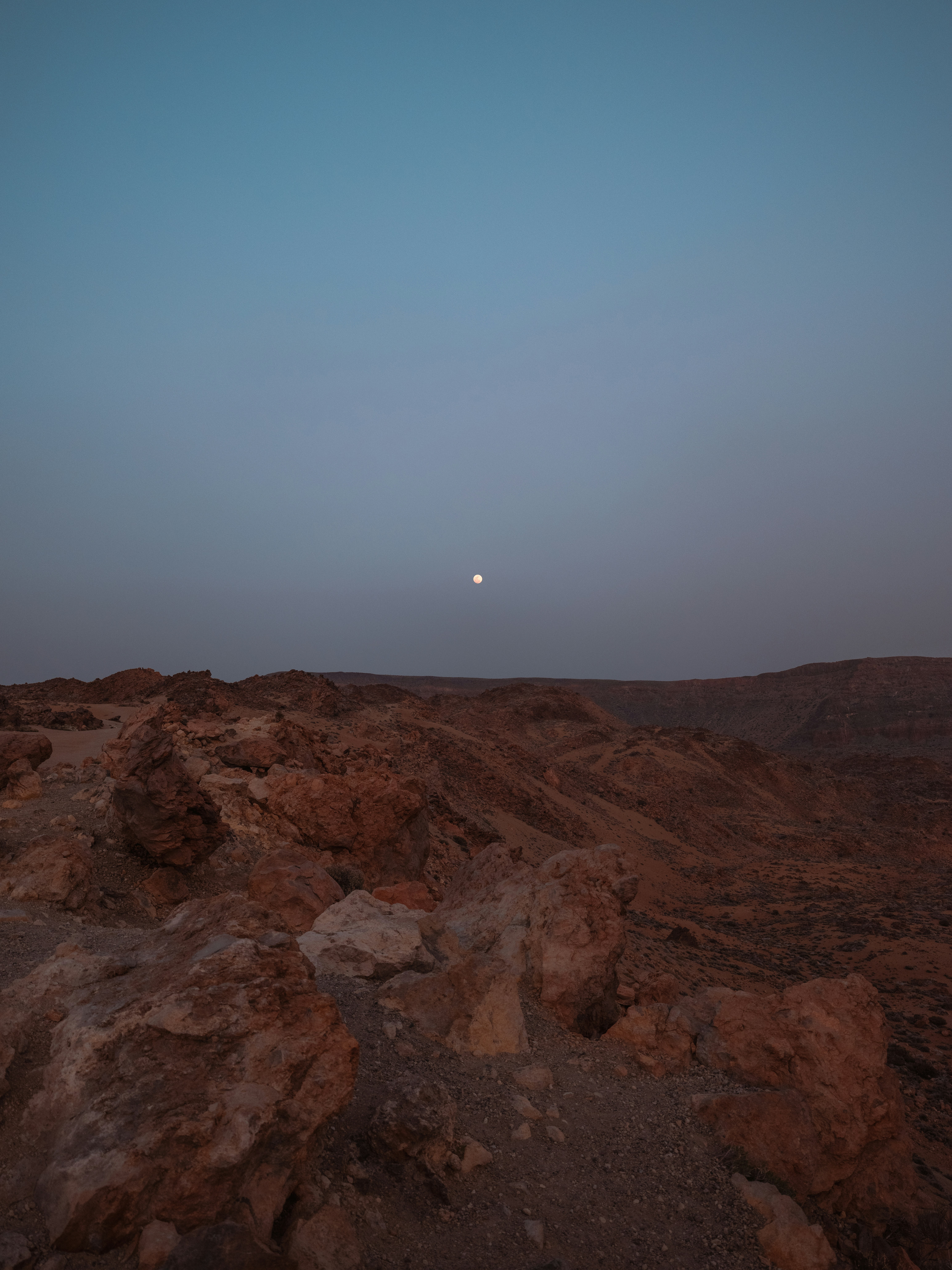 Moon Over Red Dunes: Distant Glow in Dusky Terrain