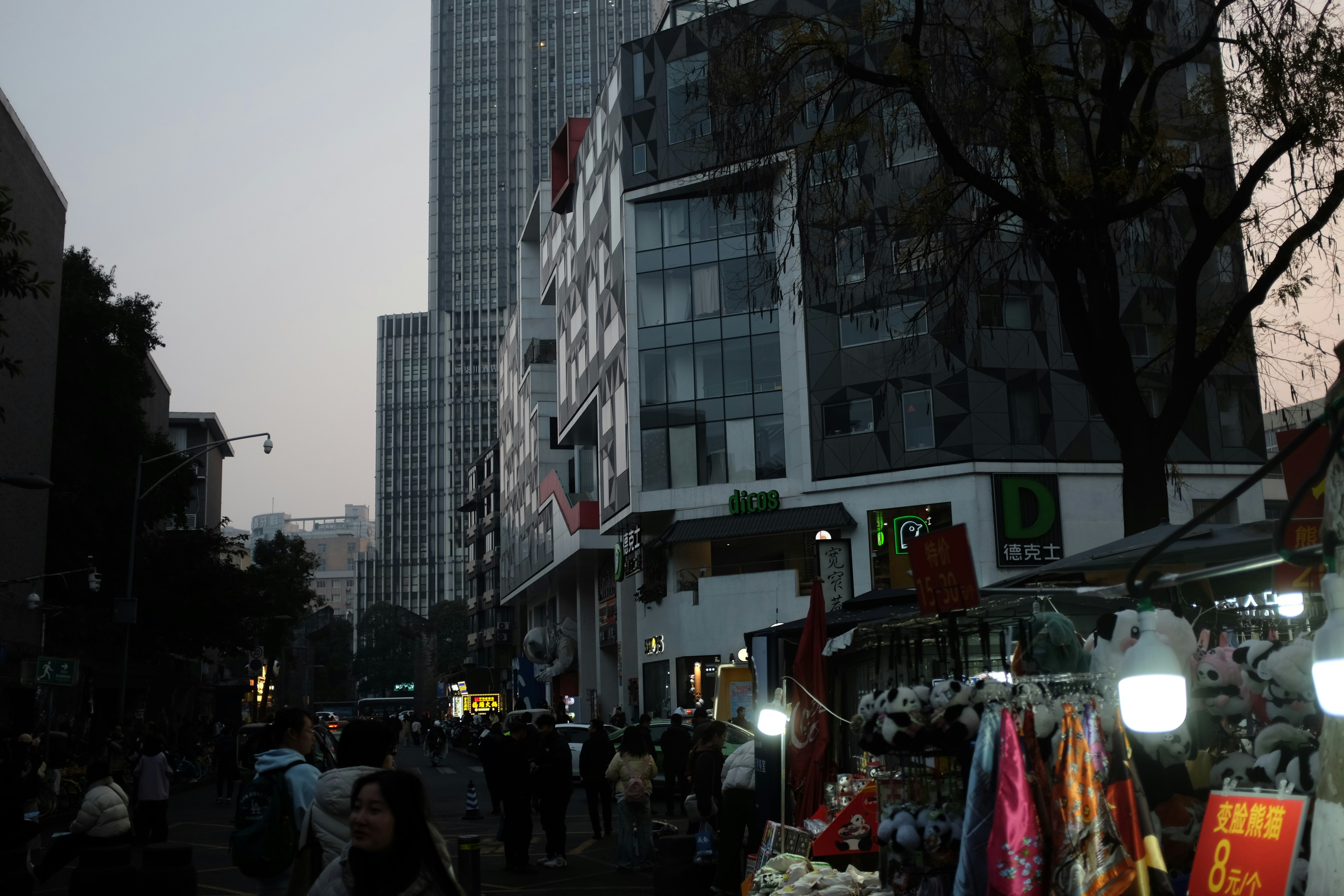 Urban Evening Market Amid Tall Glass and Shadowed Trees