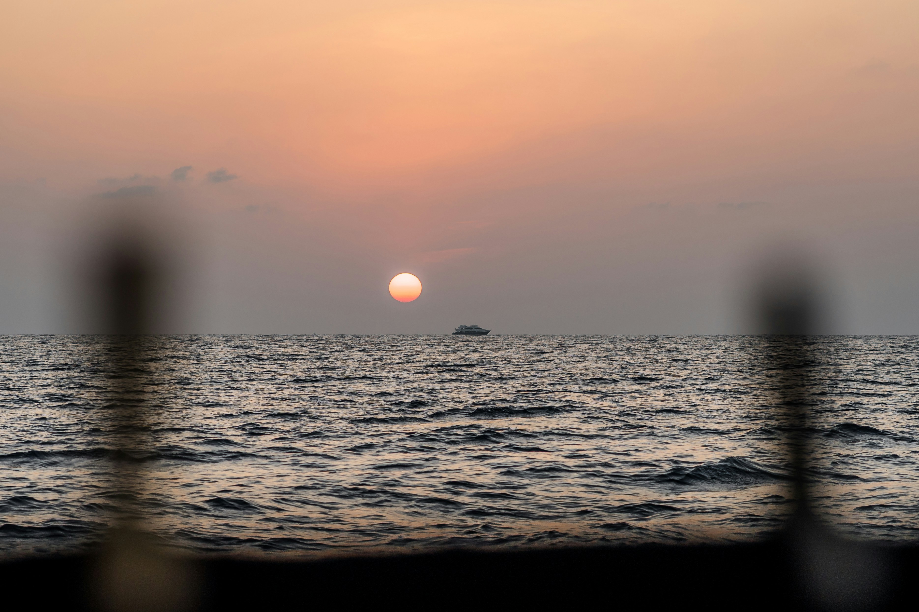 Sunset Over Quiet Seas: A blurred foreground frames the horizon