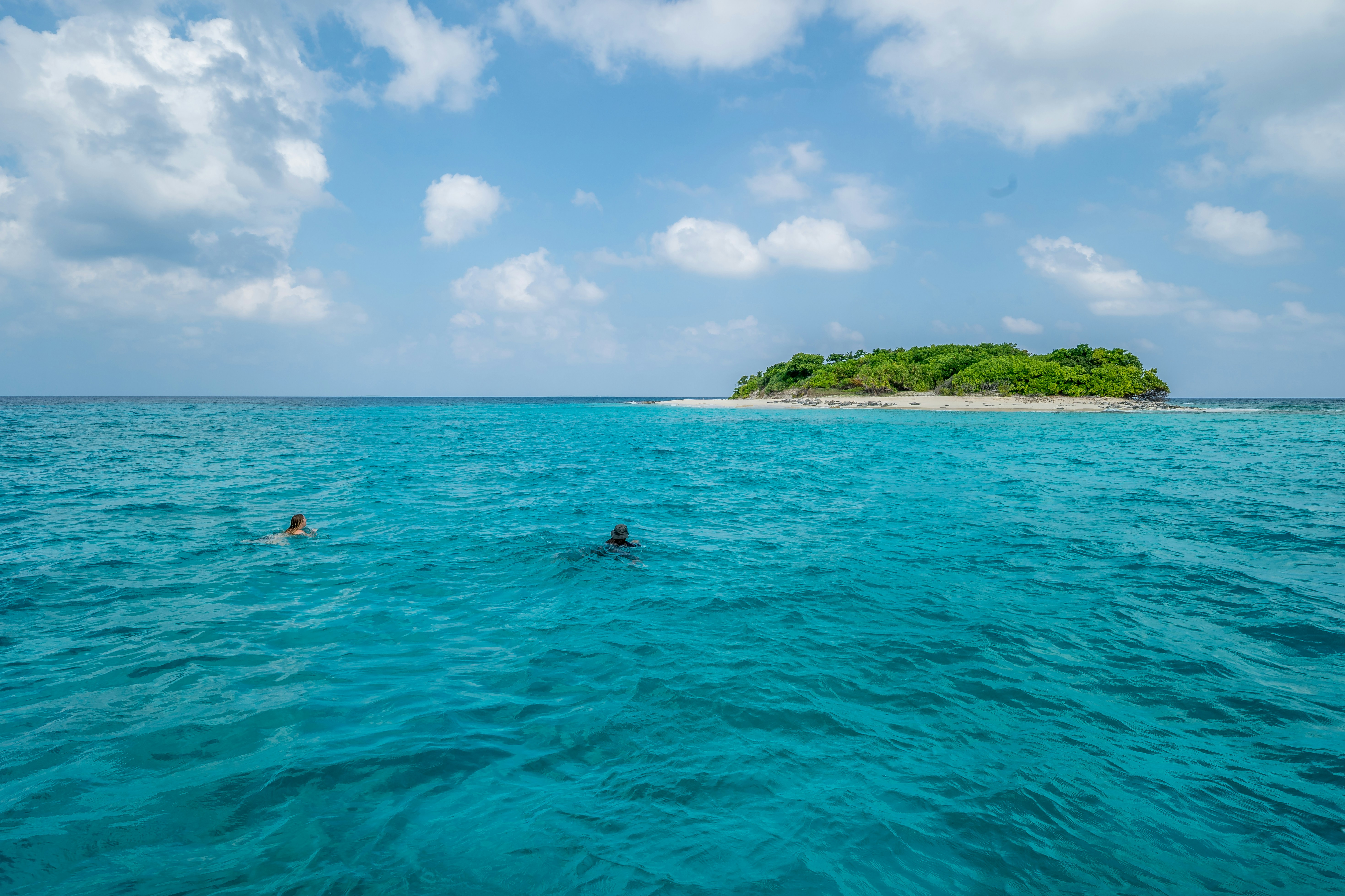 Teal Oceanline: swimmers near a distant tropical island