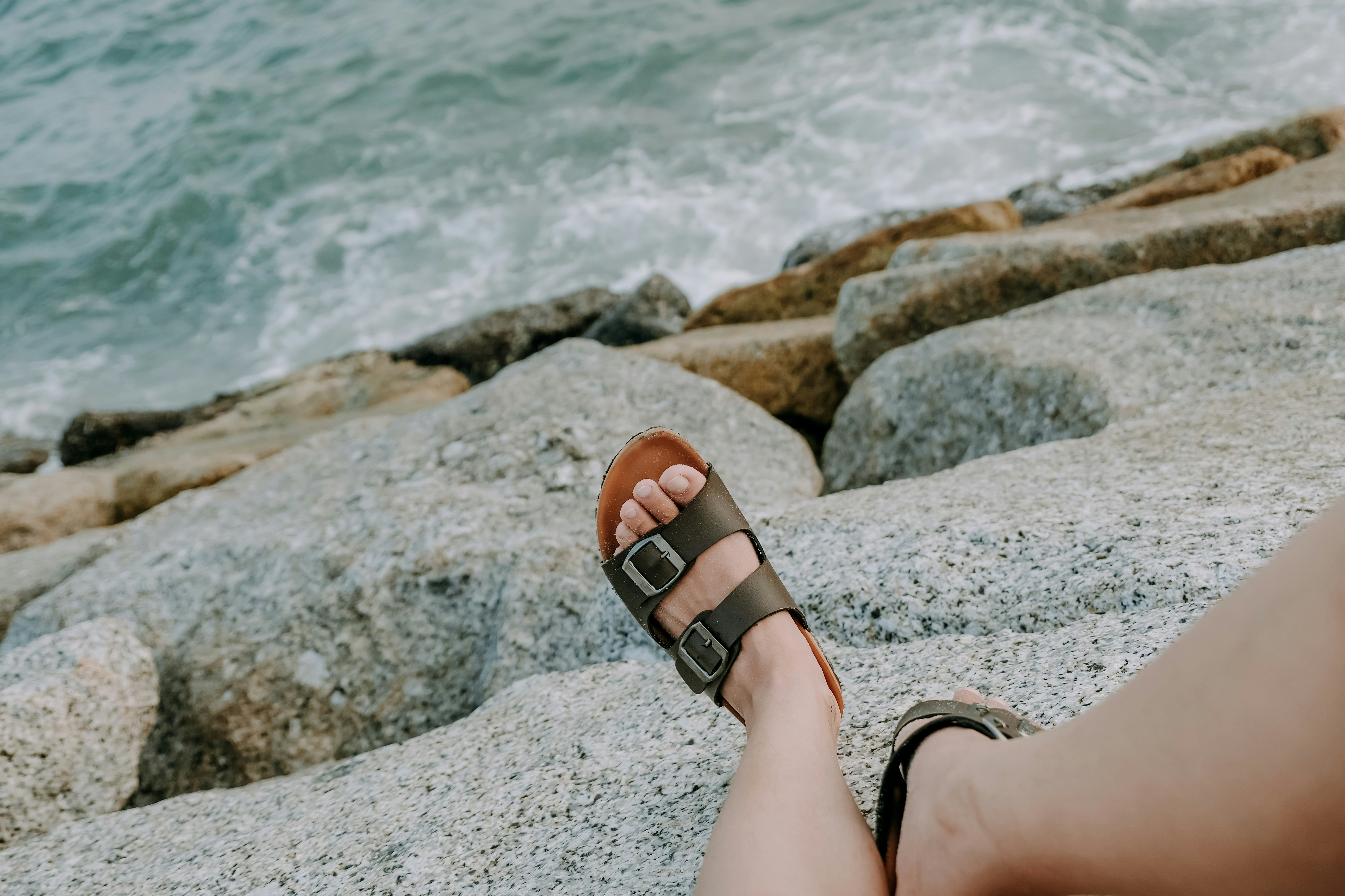 Feet in Sandal Cliffs: A Pair of Feet Rest by the Shore