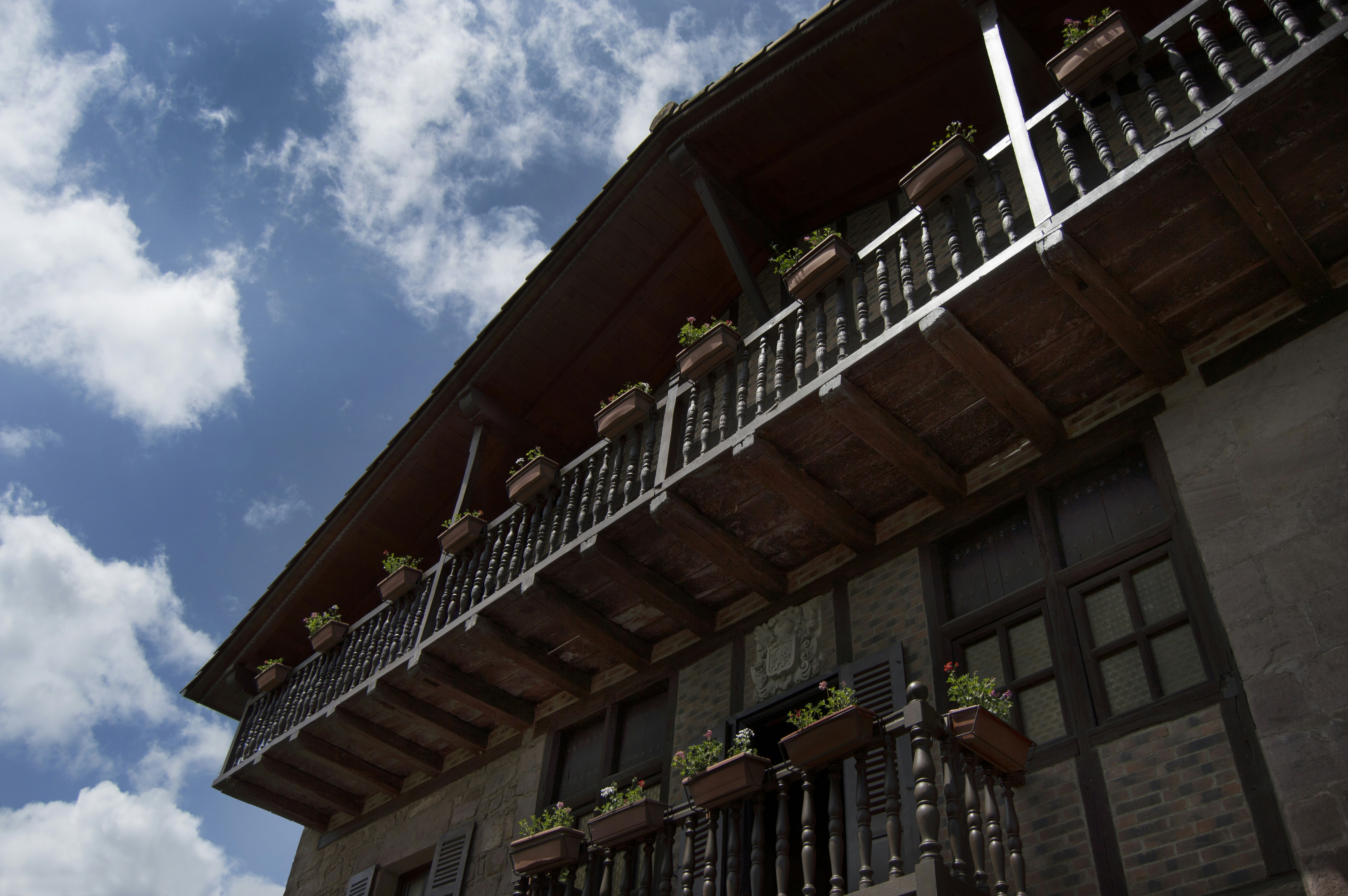 Stone Facade with Floral Balcony Overhang Against a Blue Sky