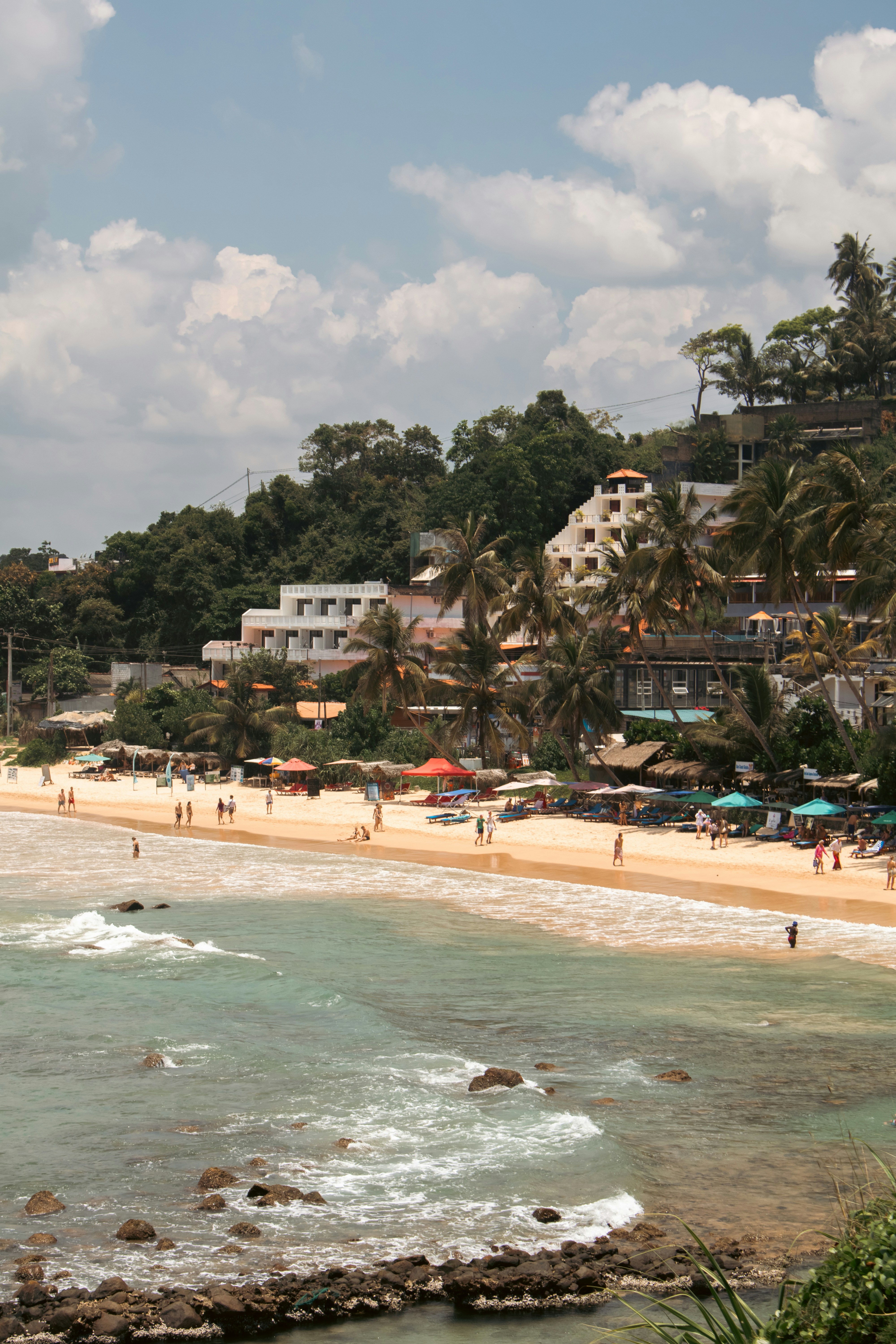Sunny Coastal Village: Palm-lined Beachfront Beneath a Pueblo-style Cliffscape