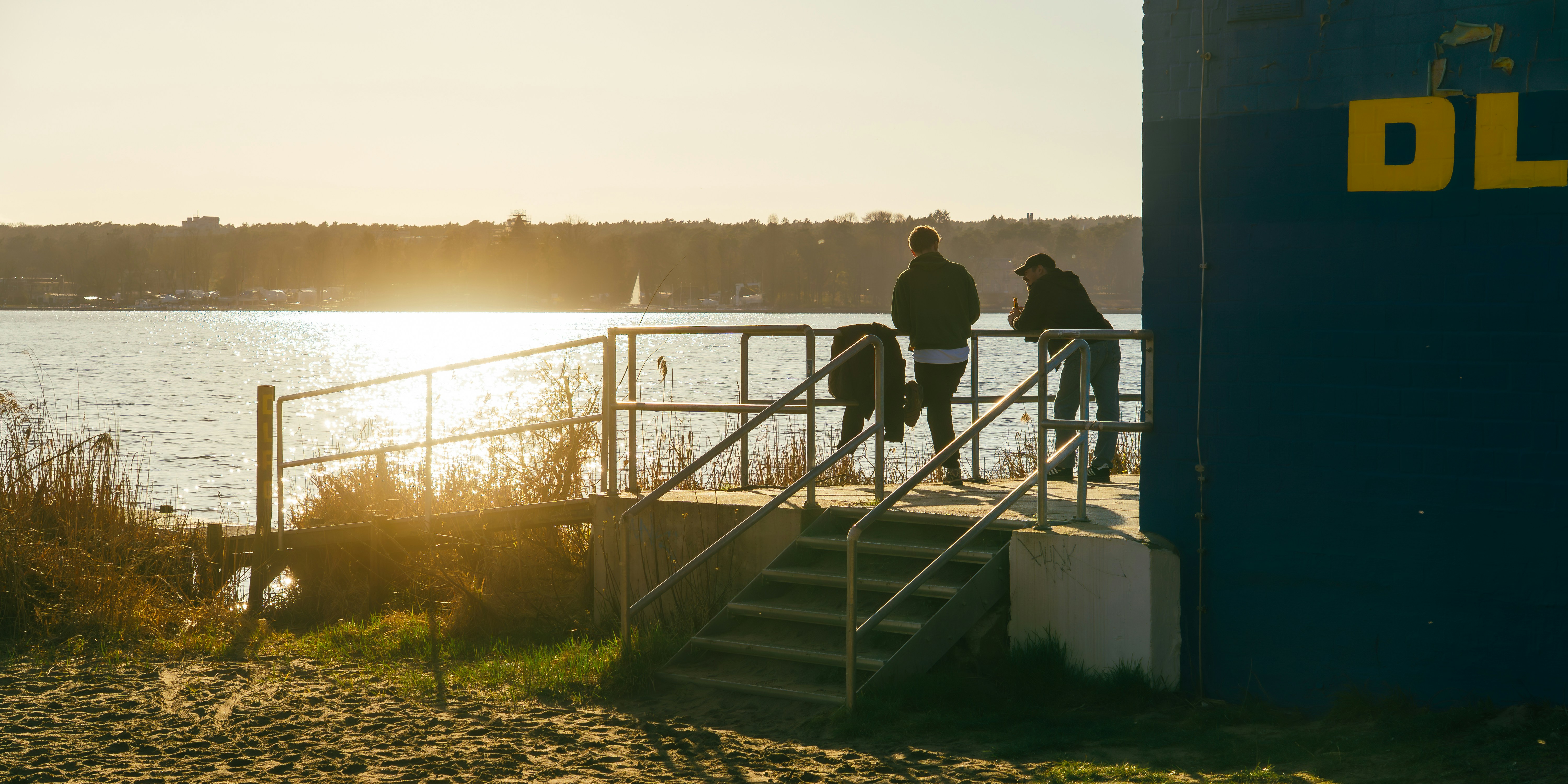Sunlit Docks: Two Figures at the Water's Edge