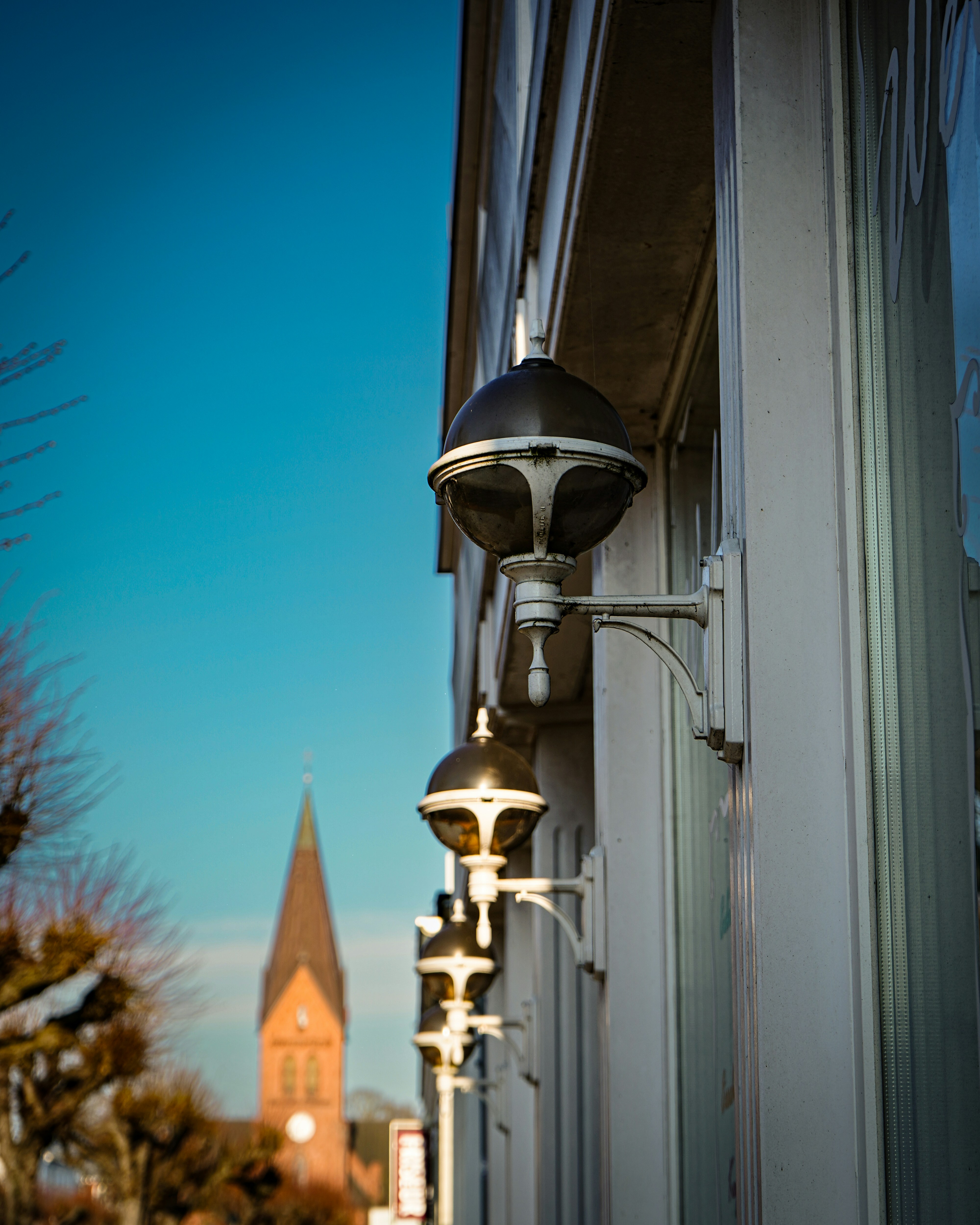 Lamp-lined storefront Receding into a Distinct Church Spire