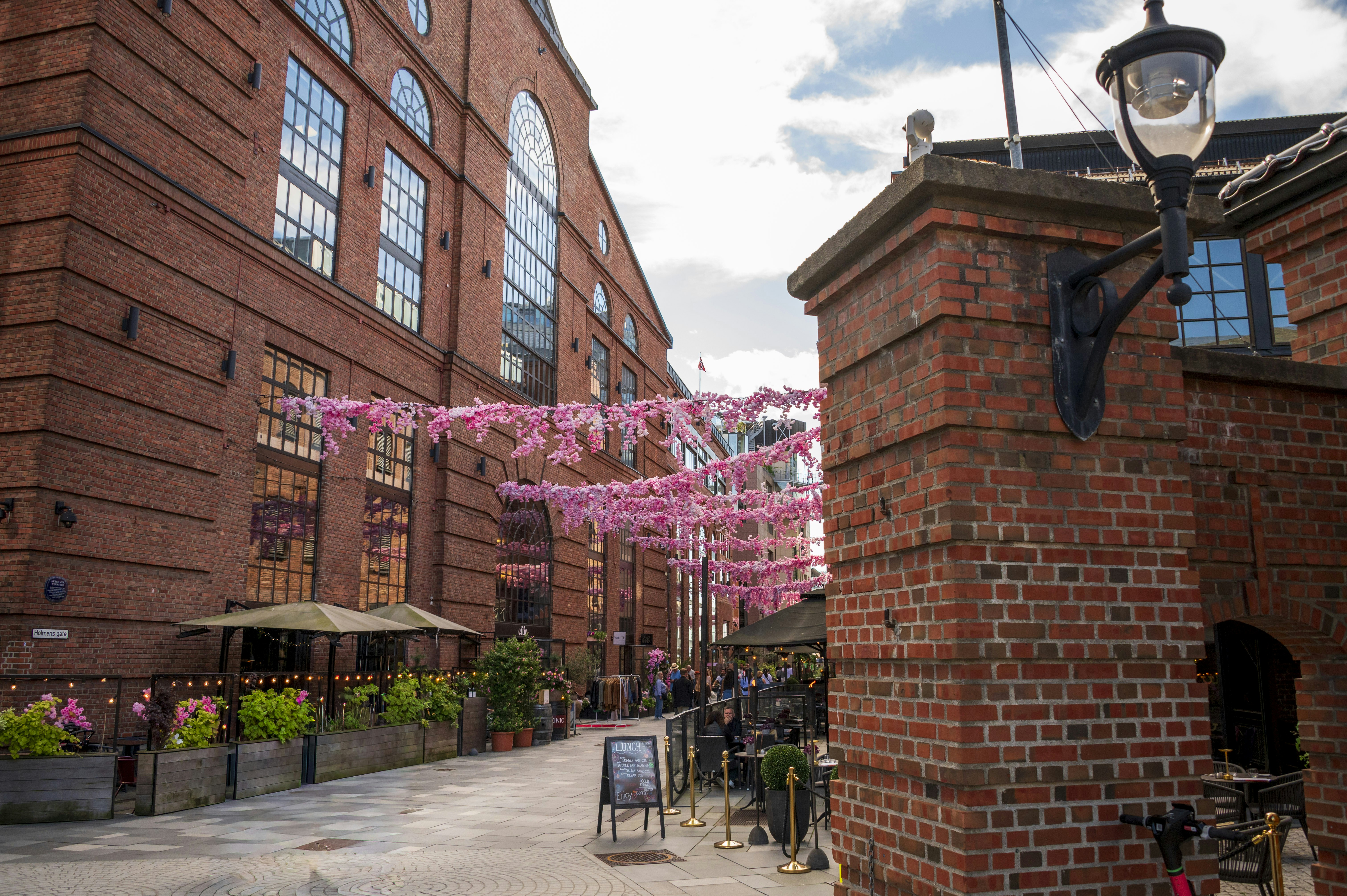 Brick Courtyard Alight with Pink Canopy Under a Lofty Industrial Roofline