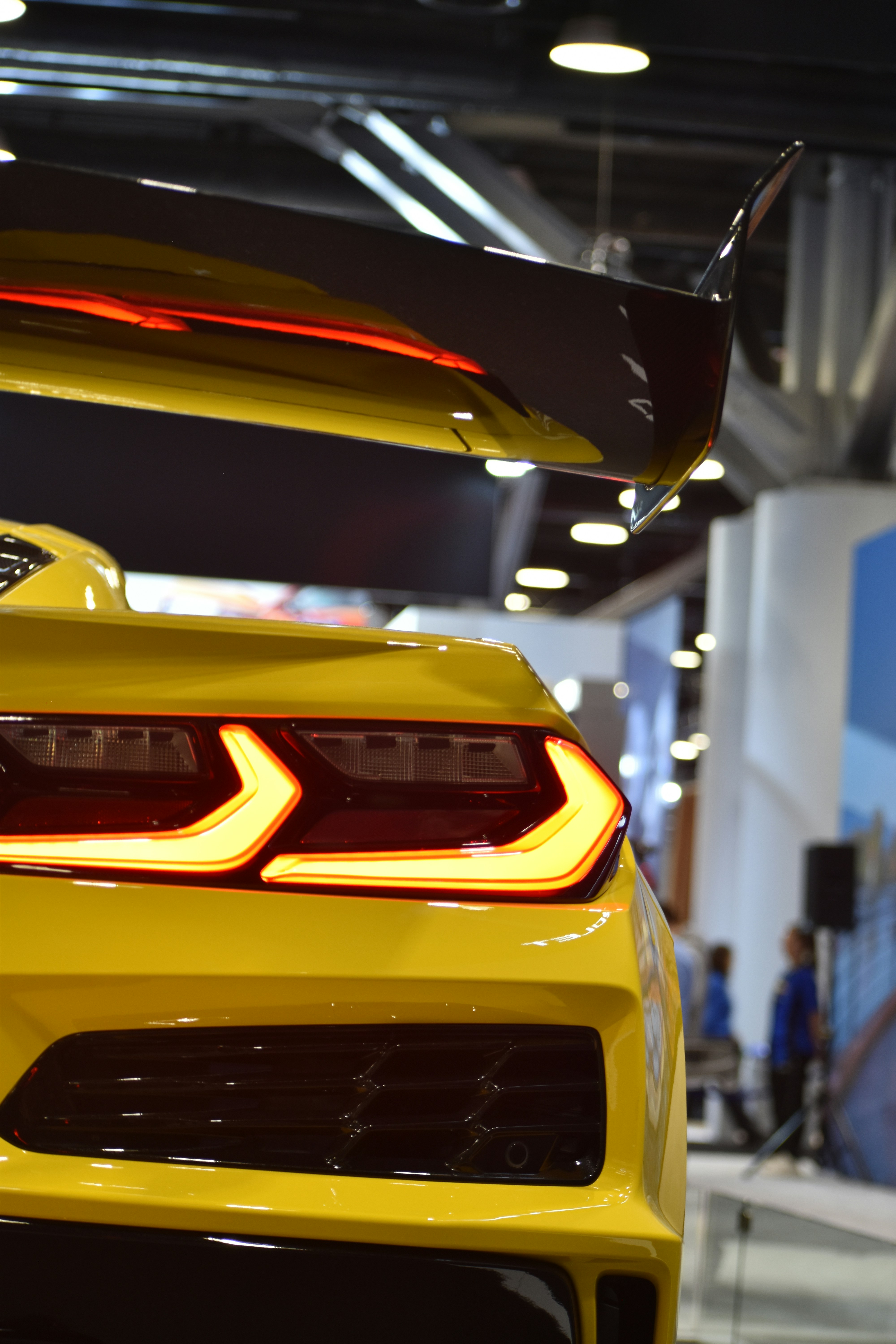 Rear-View Yellow Racer: Tail Lights in Focus Under Showroom Lights