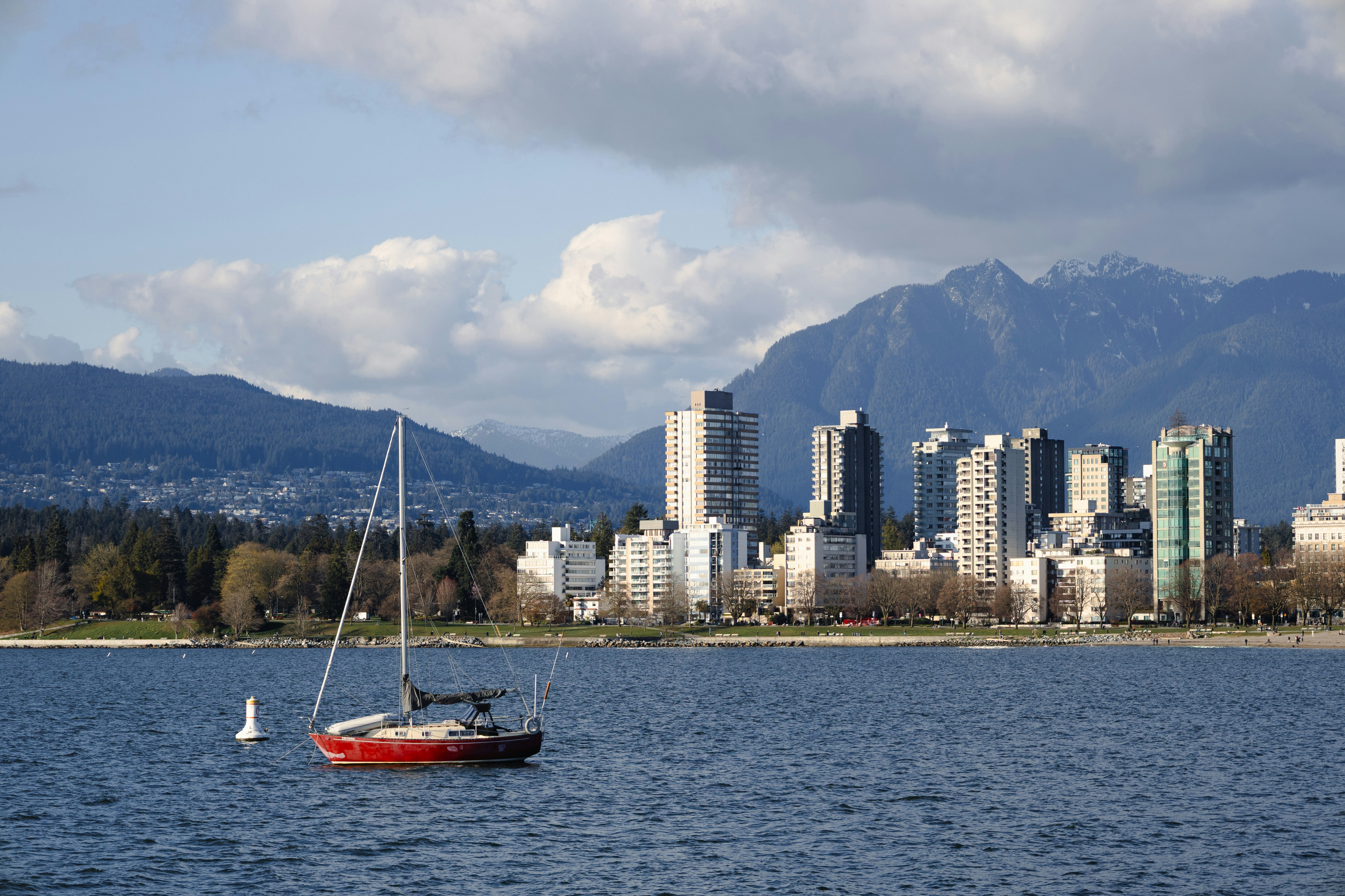 Sailboat on a calm harbor, cityscape and mountains in the distance