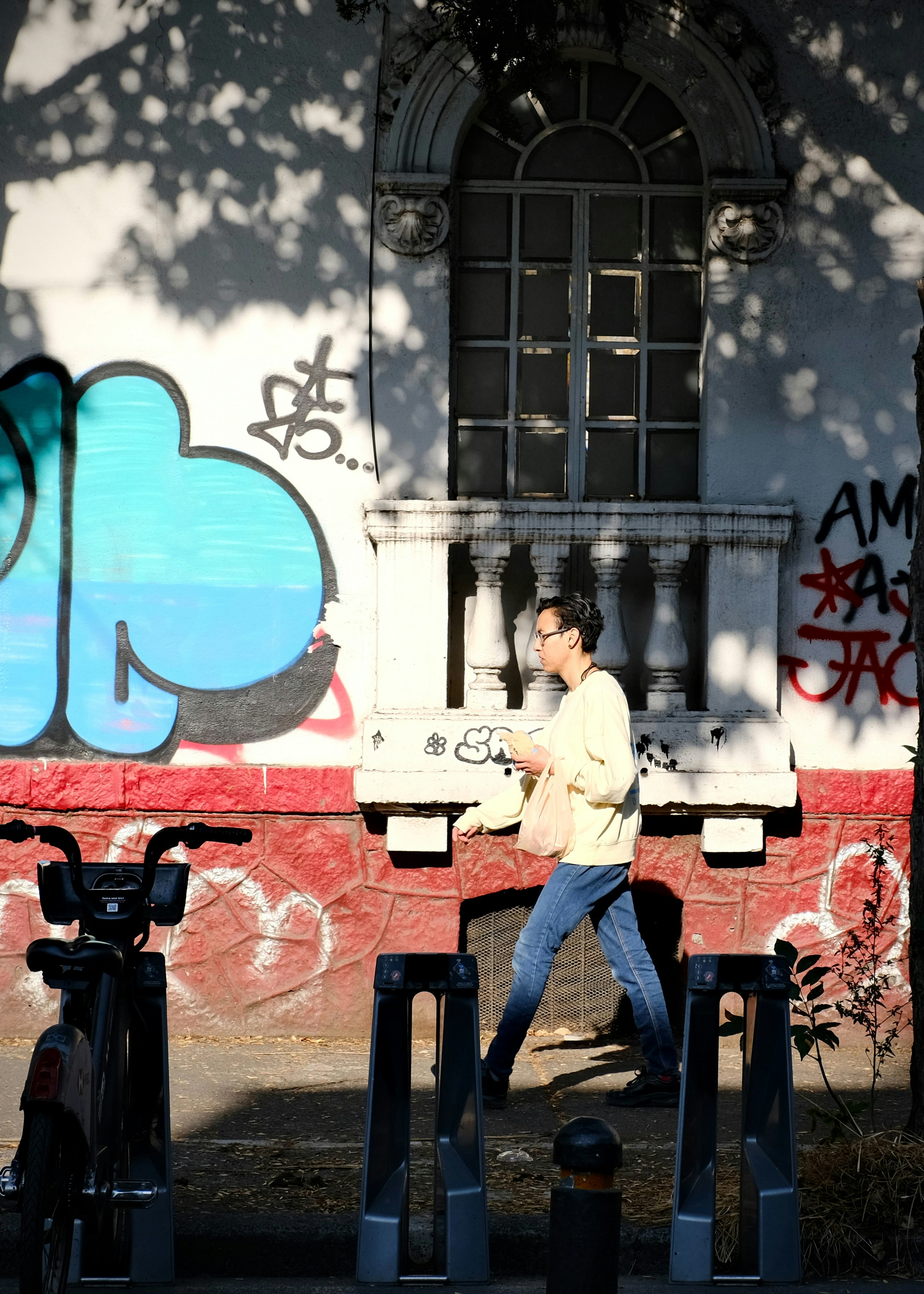 Urban Stroll in Front of a Graffitied Windowed Wall