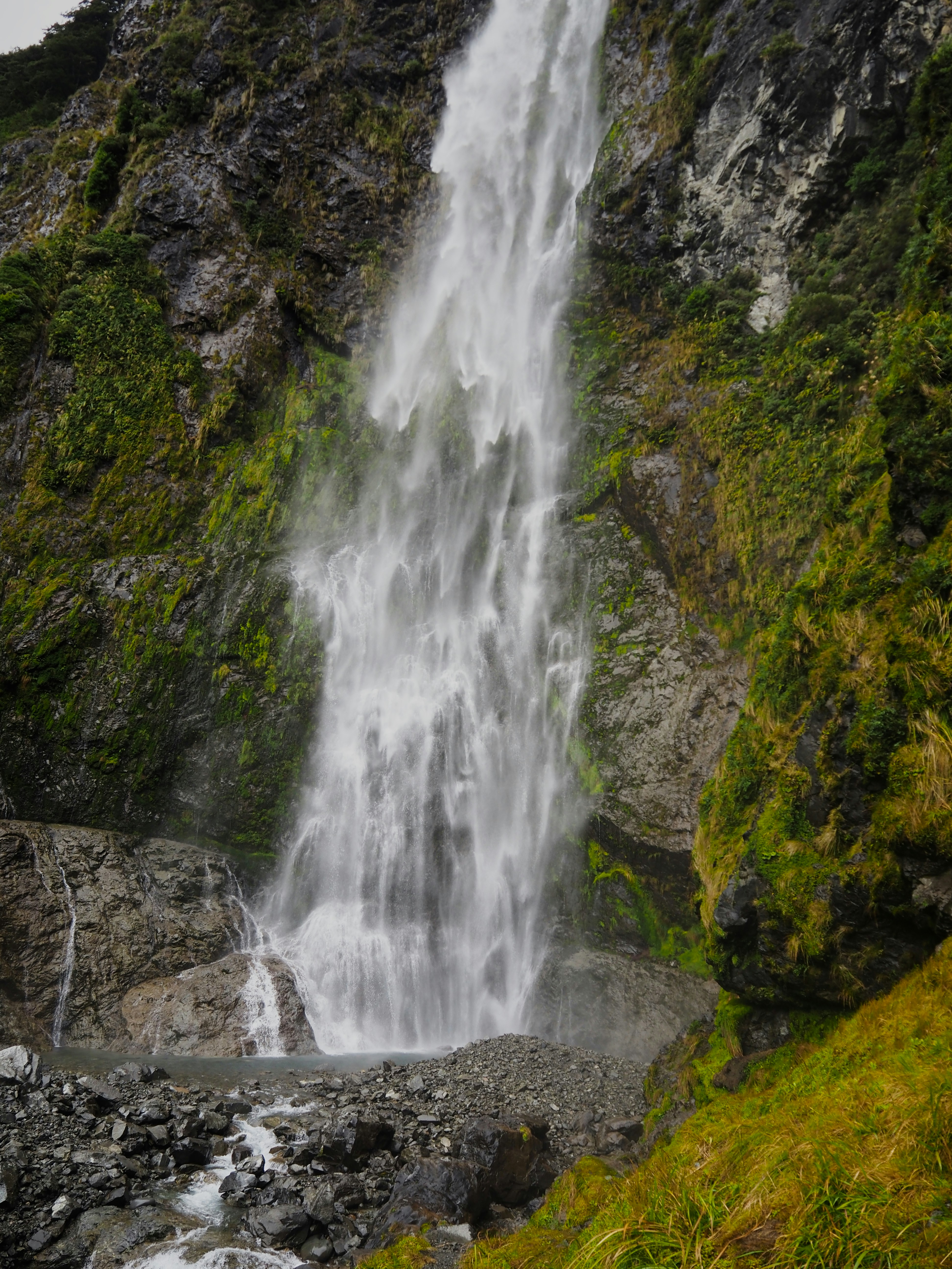 Forest Cascade: A Narrow White Veil Carving Through Mossy Cliffs