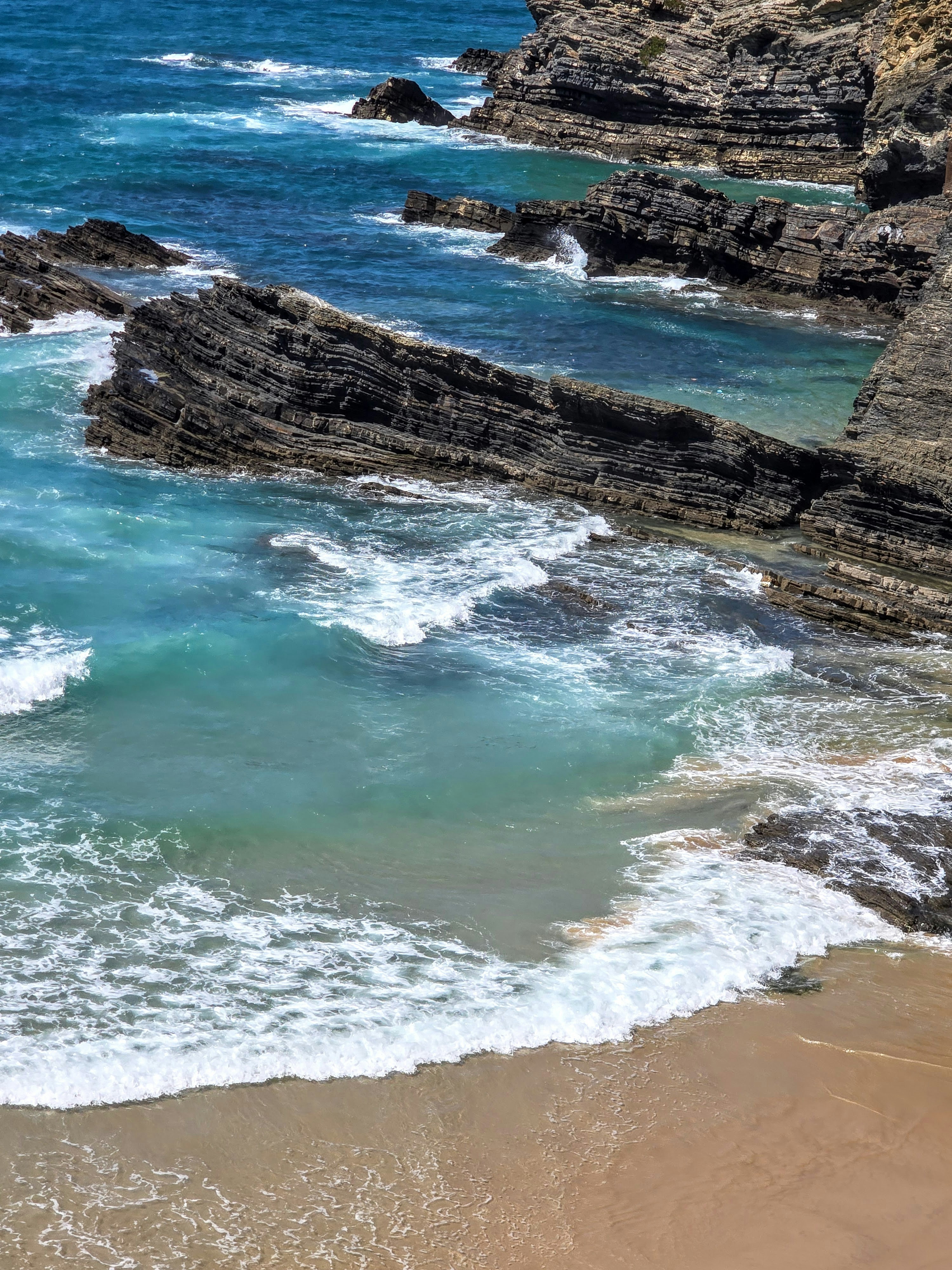 Rugged Tidemeet: Layered Cliffscape Meeting Turquoise Waters