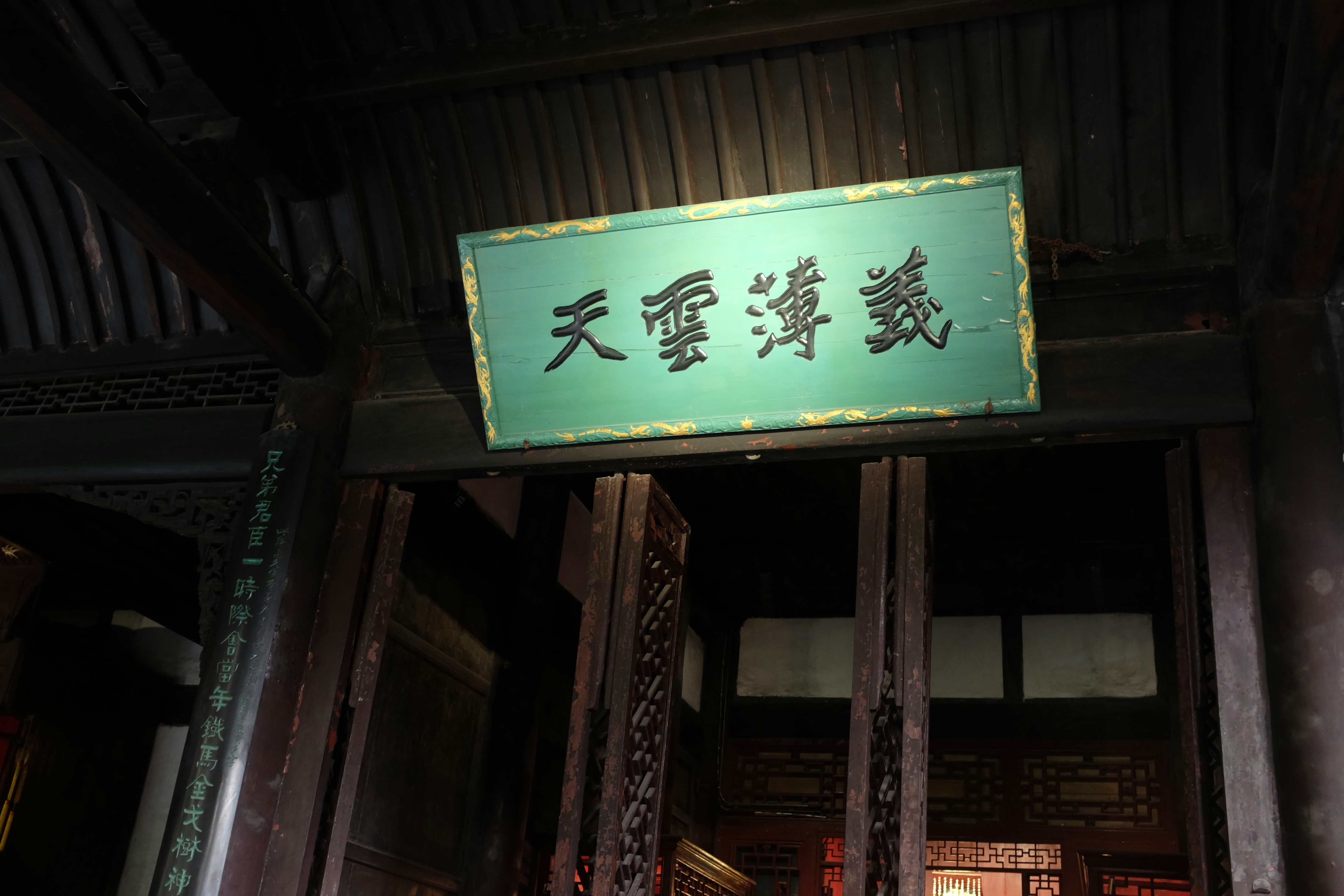 Green plaque above a carved doorway in a traditional temple