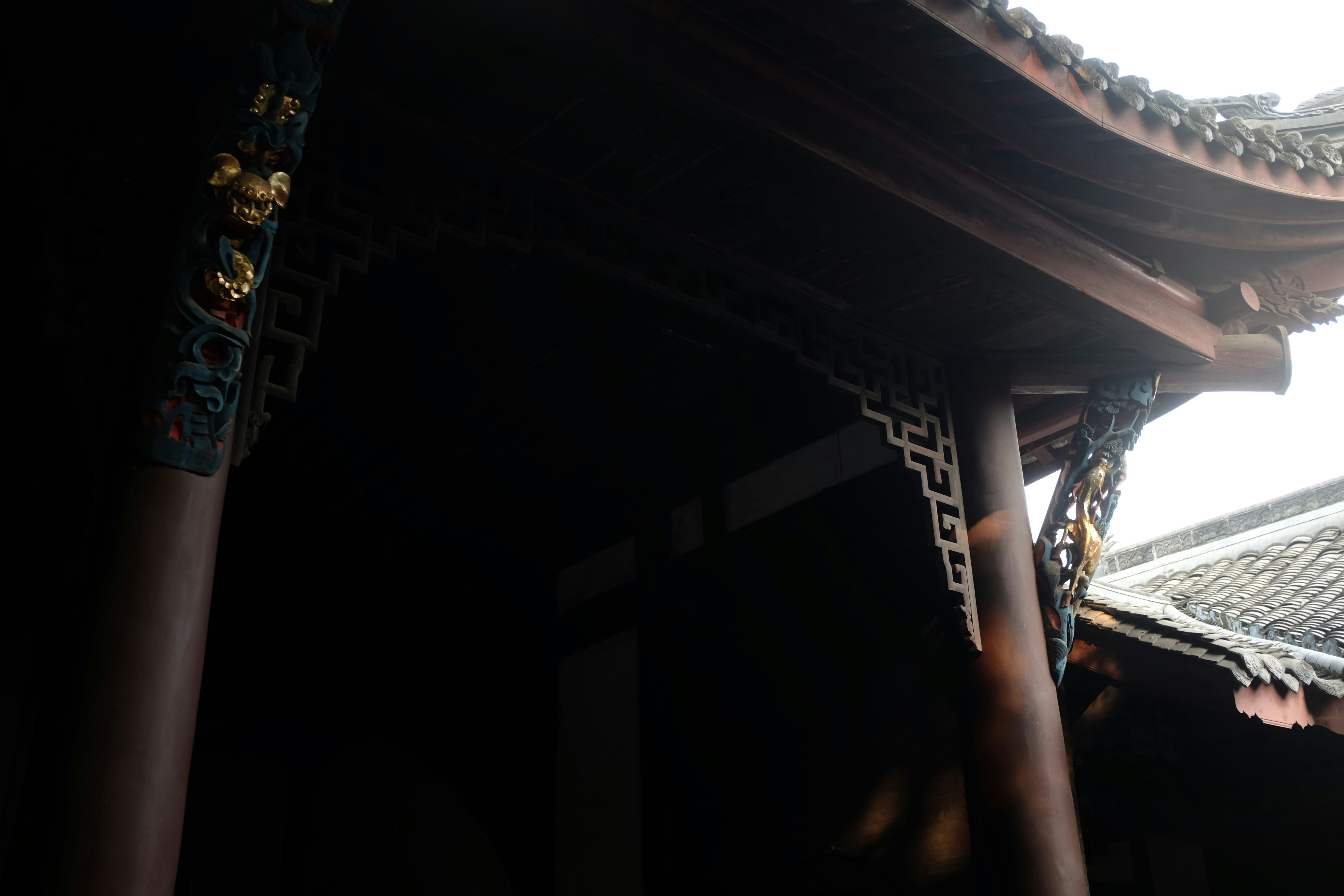 Hidden Corner of a Traditional Roof: Lanterns and Carved Columns in Shadow