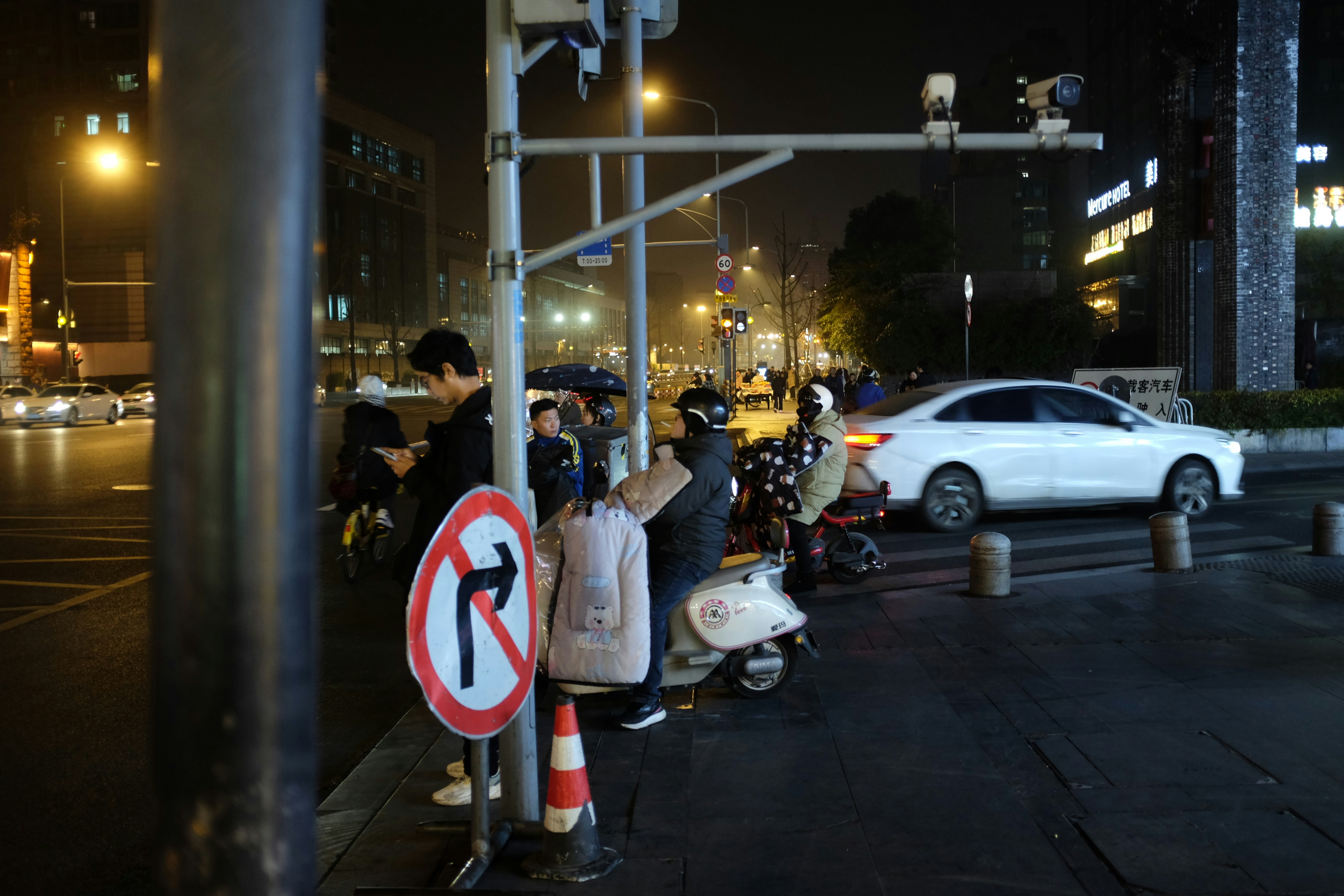Night Street Stop: People, Scooter, and Moving Traffic at the Crosswalk