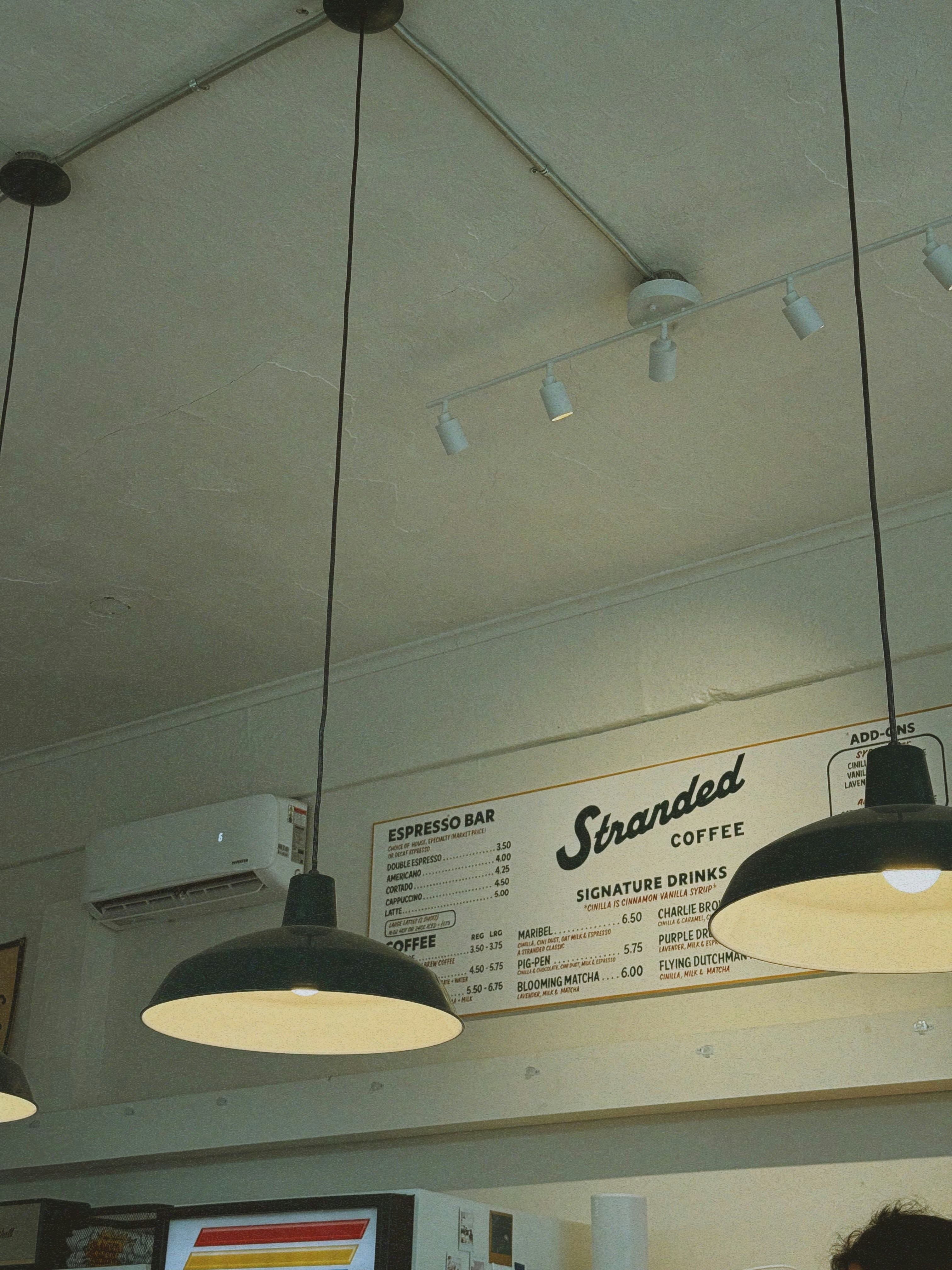Muted cafe ceiling with suspended lighting and a menu board