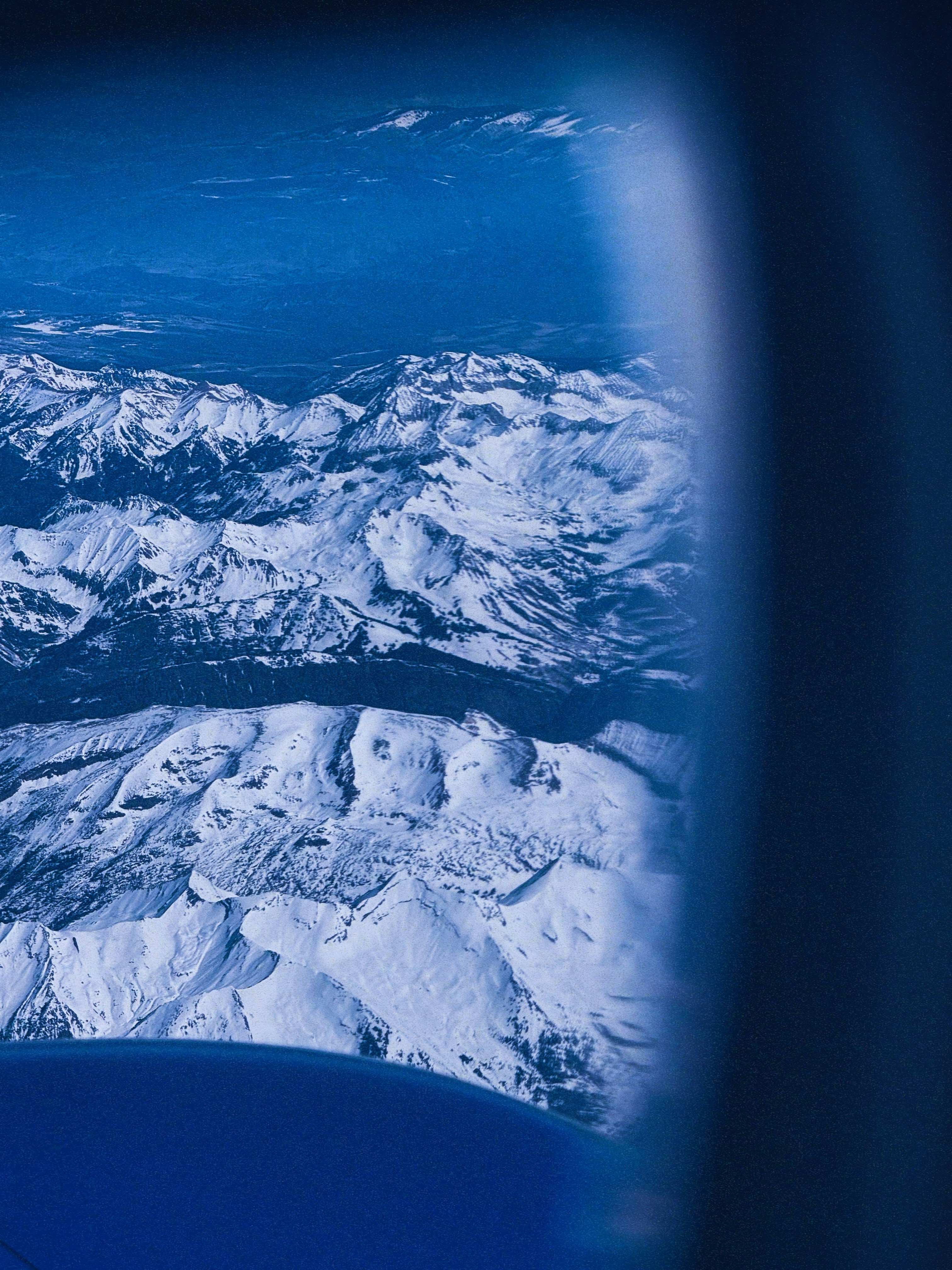 A Glimpse Through the Window: Snow-Capped Peaks Framed by Aircraft Window Architecture