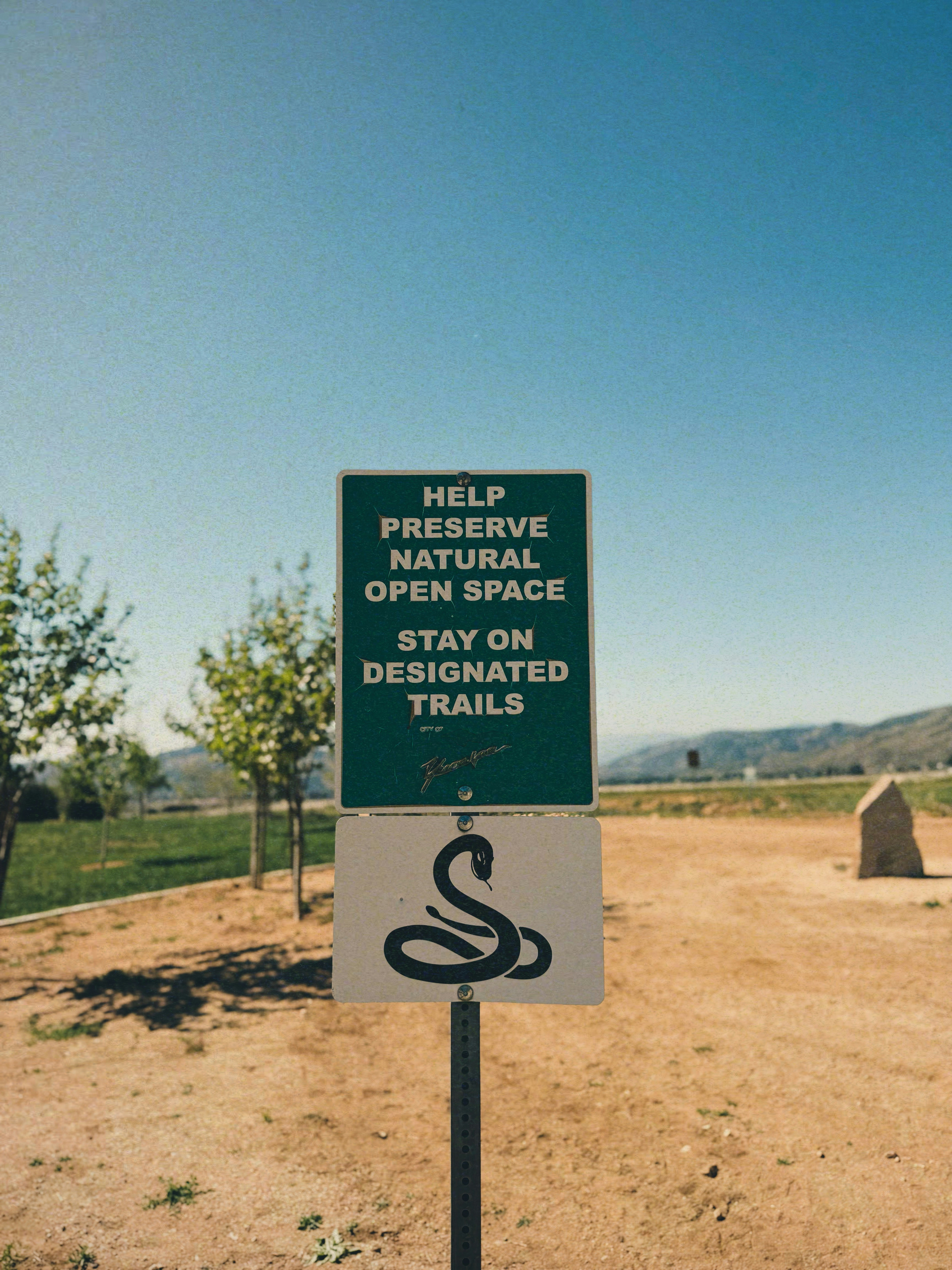 Trail Sign in Arid Field: A Quiet Call to Stay on Designated Paths