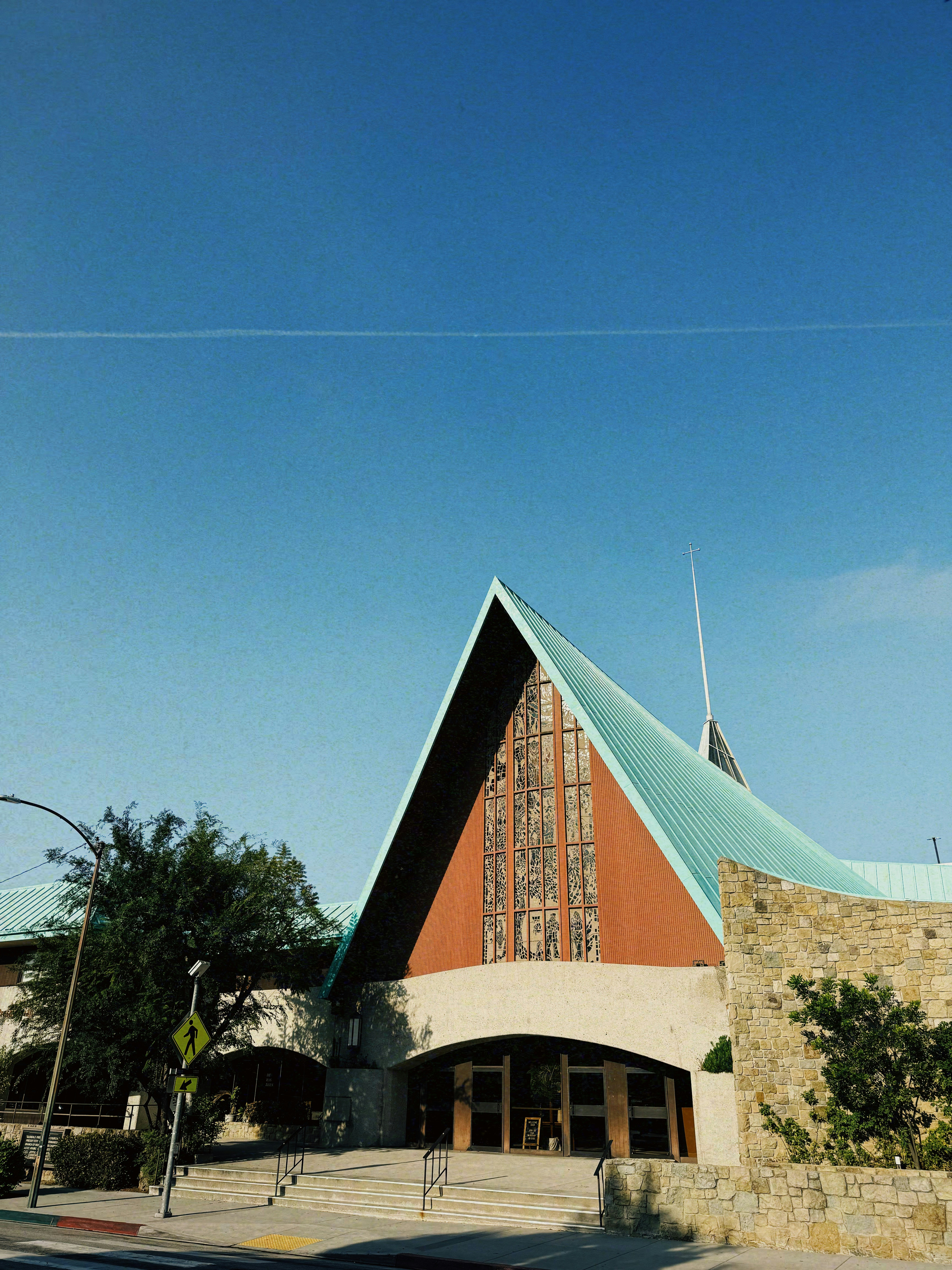 A triangular church crown rises above a sunlit street