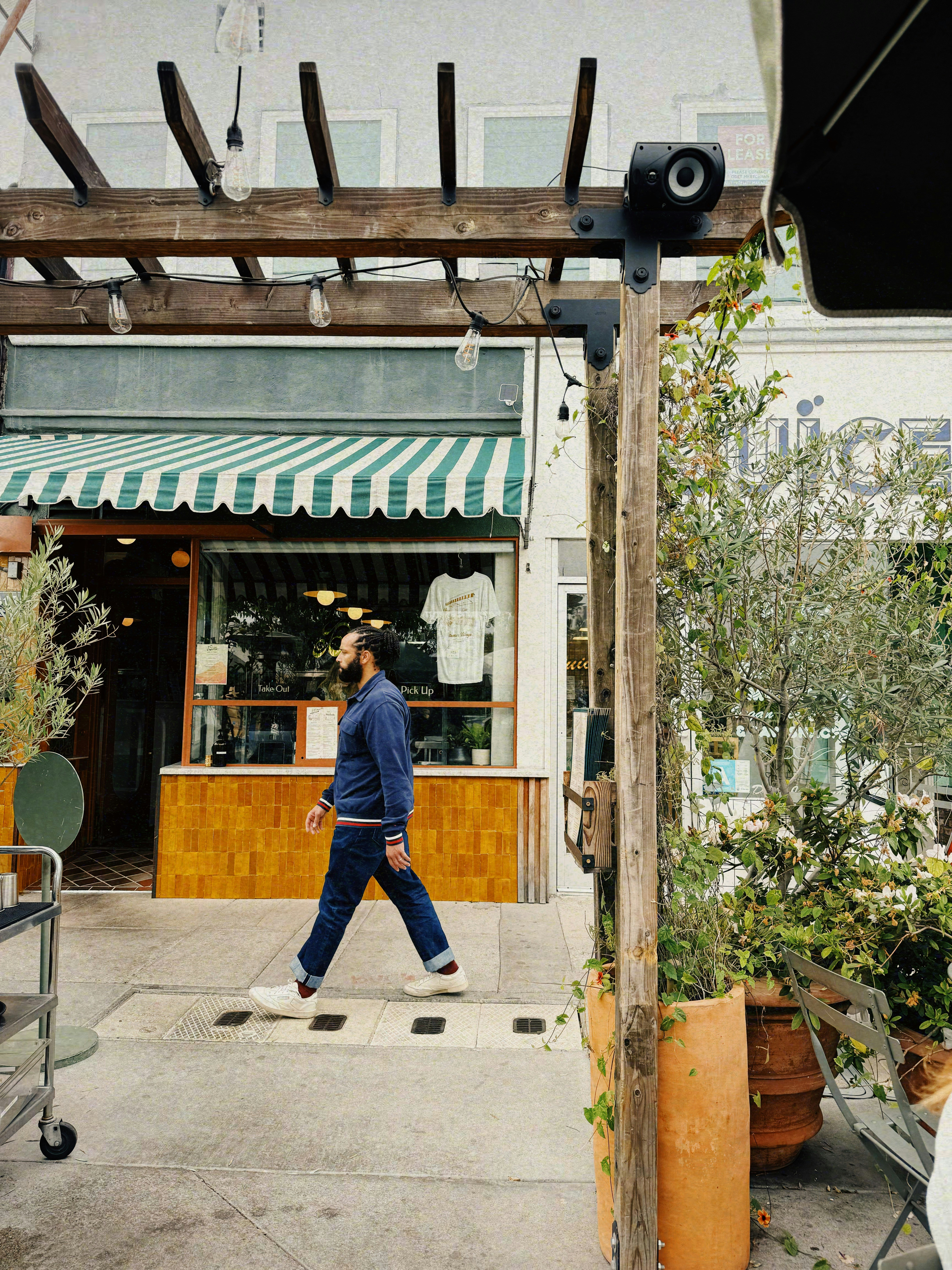 A Quiet Stride Through a Sunlit Urban Café Corridor
