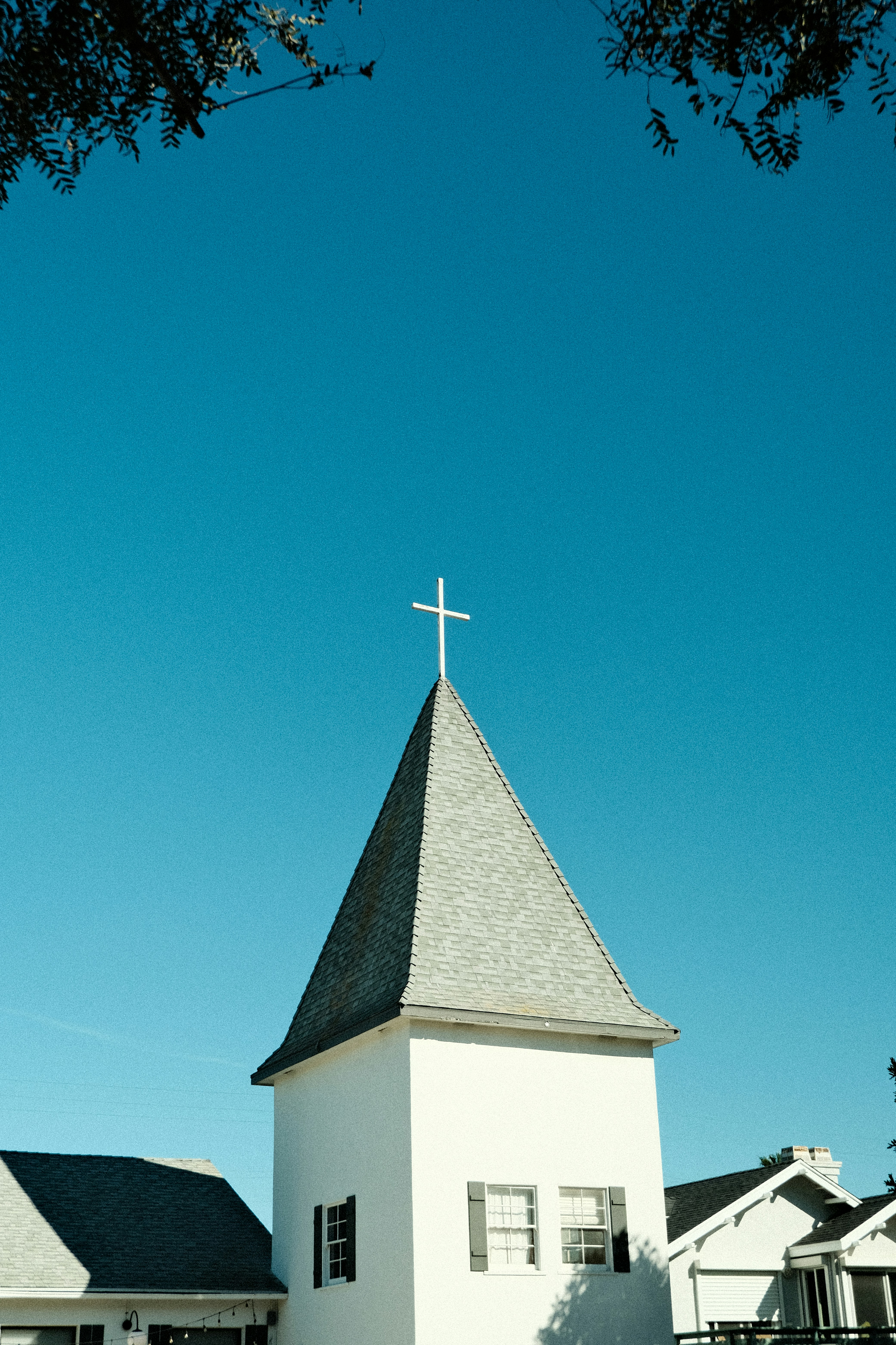 Cross atop a church steeple under a clear blue sky