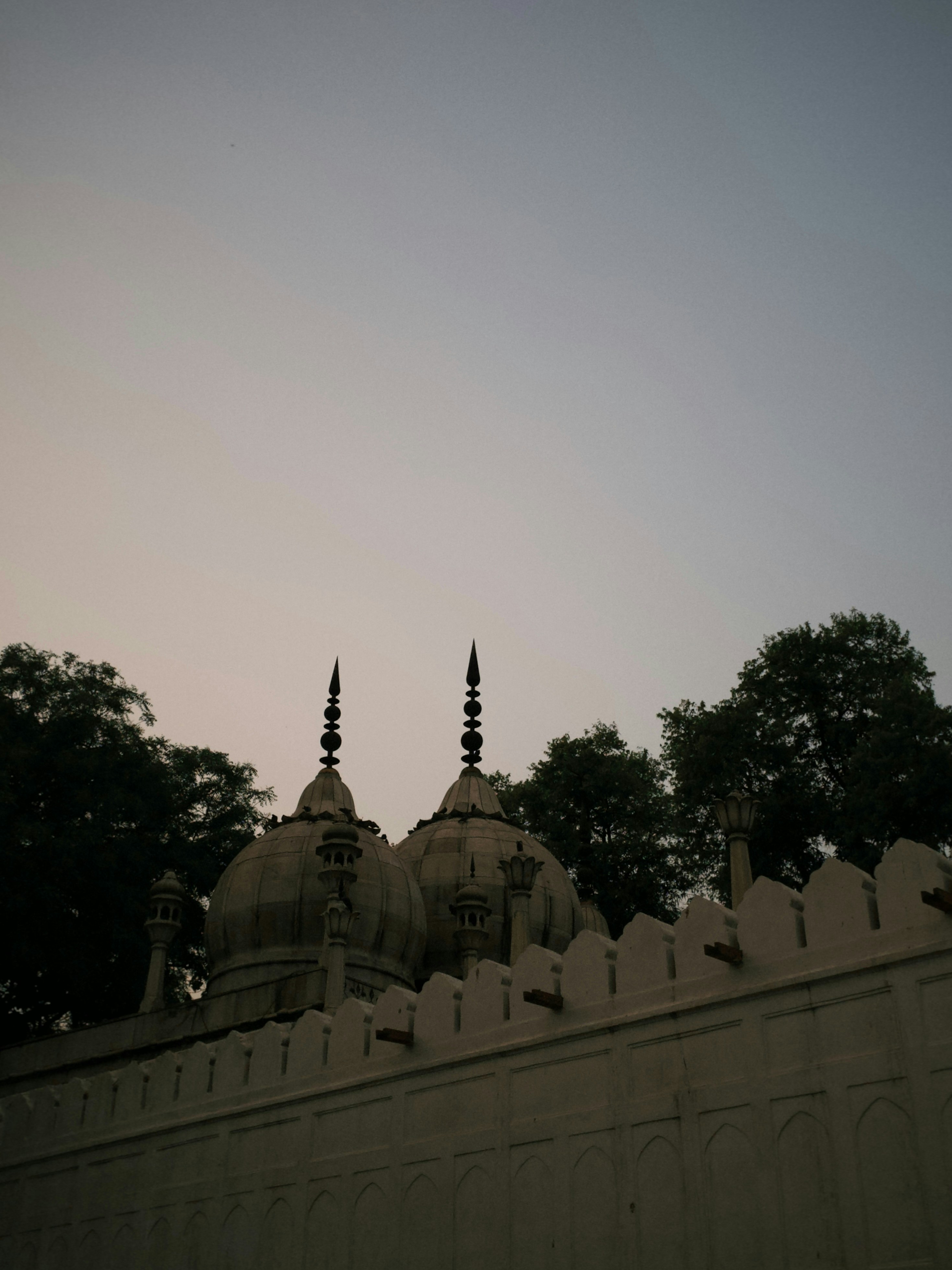 Silhouetted Domes Against a Dusk Sky Above a Historic Wall