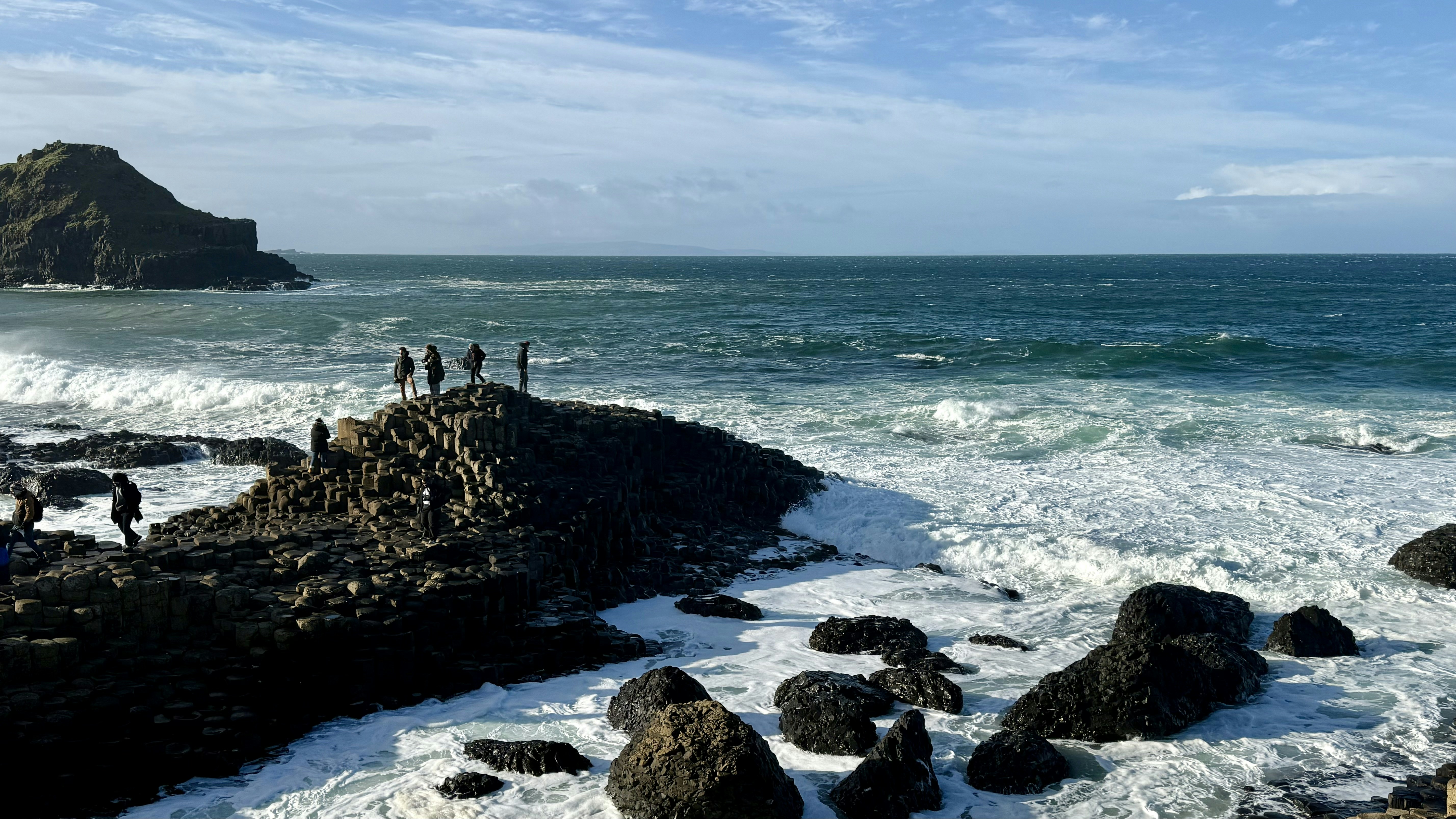 Rocky Promenade at Sea: Figures Against the Tide