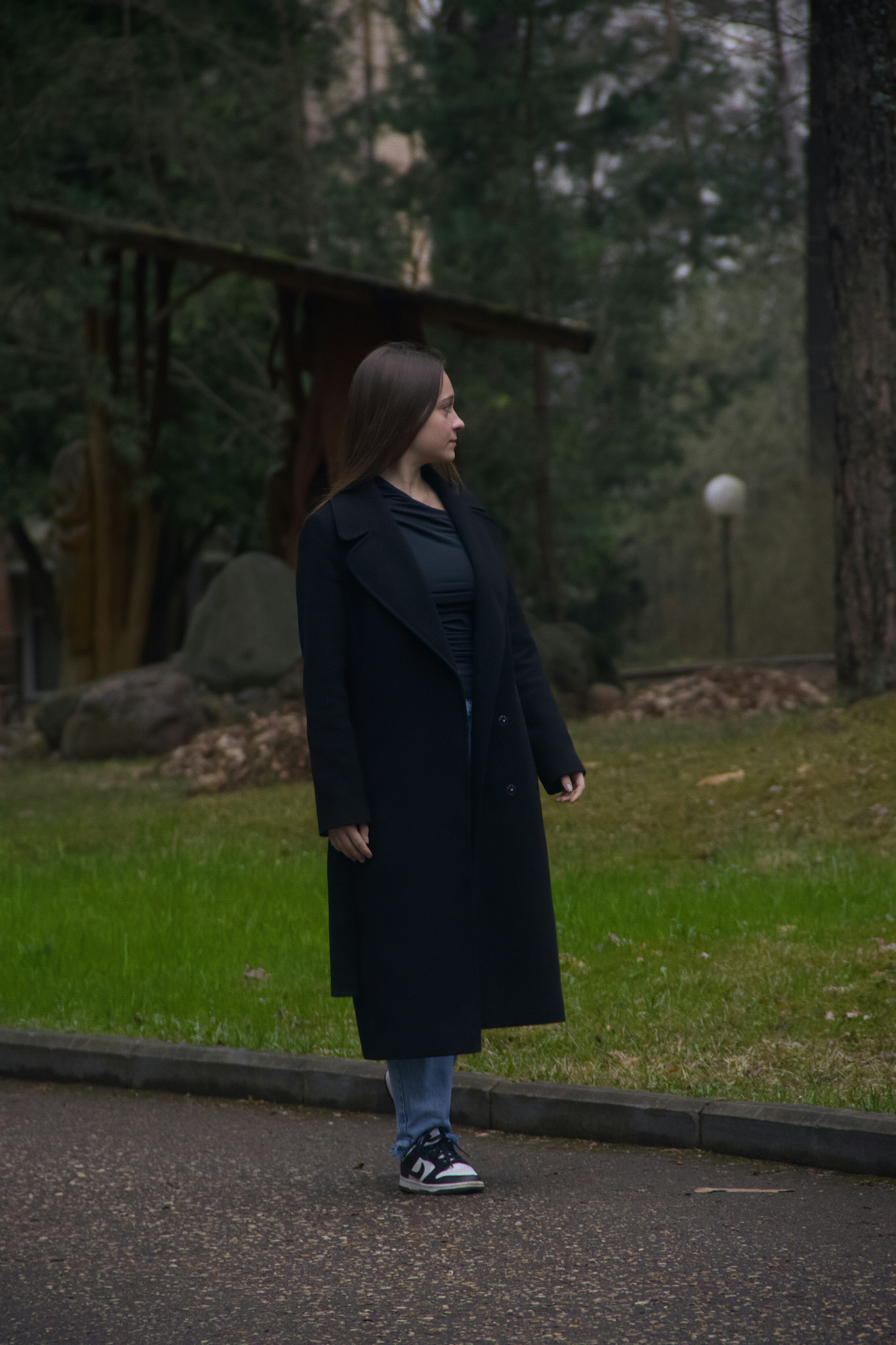 Woman in a dark coat Strolling Through a Quiet Park at Dusk