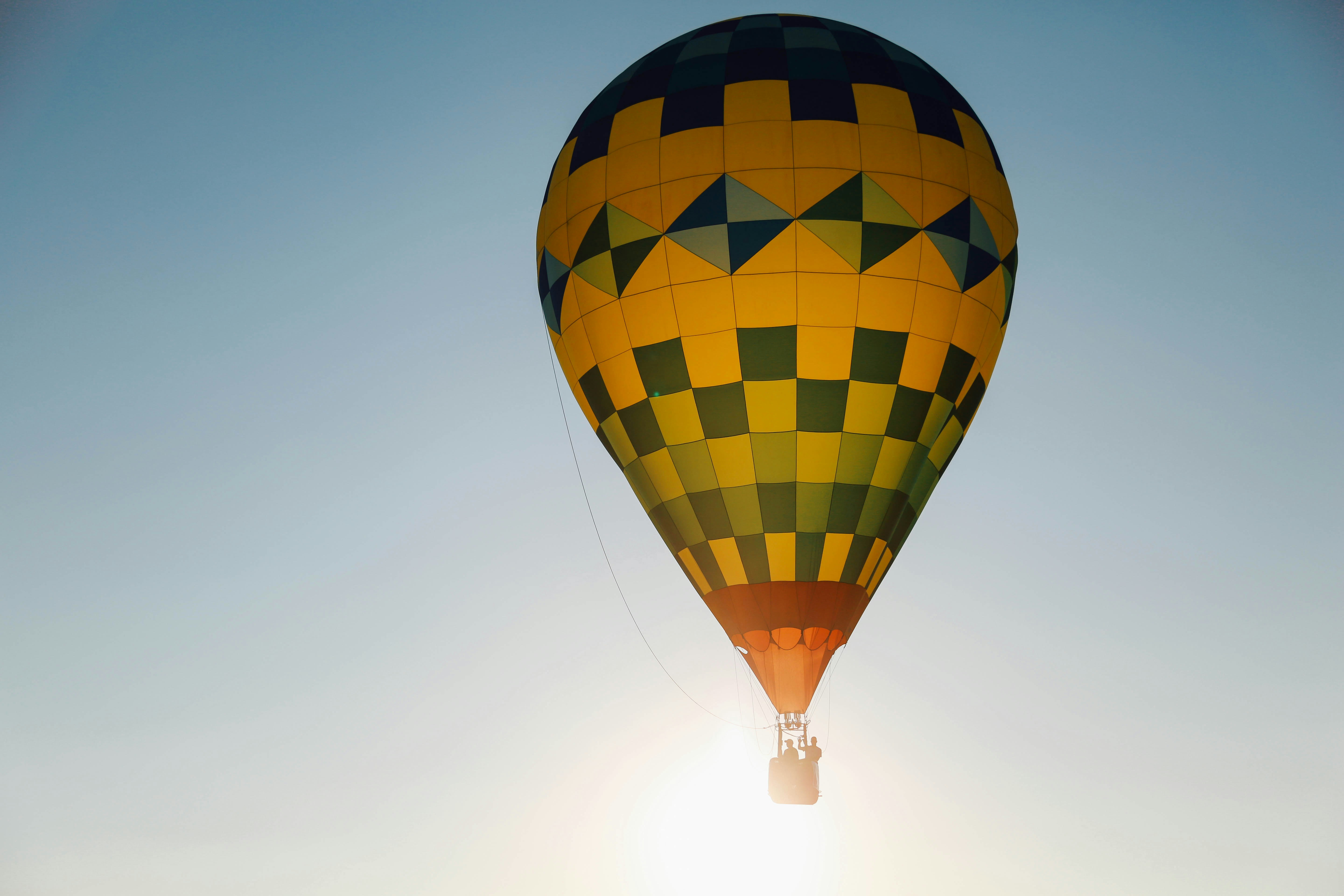 Rising beacon: a sunlit hot air balloon drifting against a clear morning sky