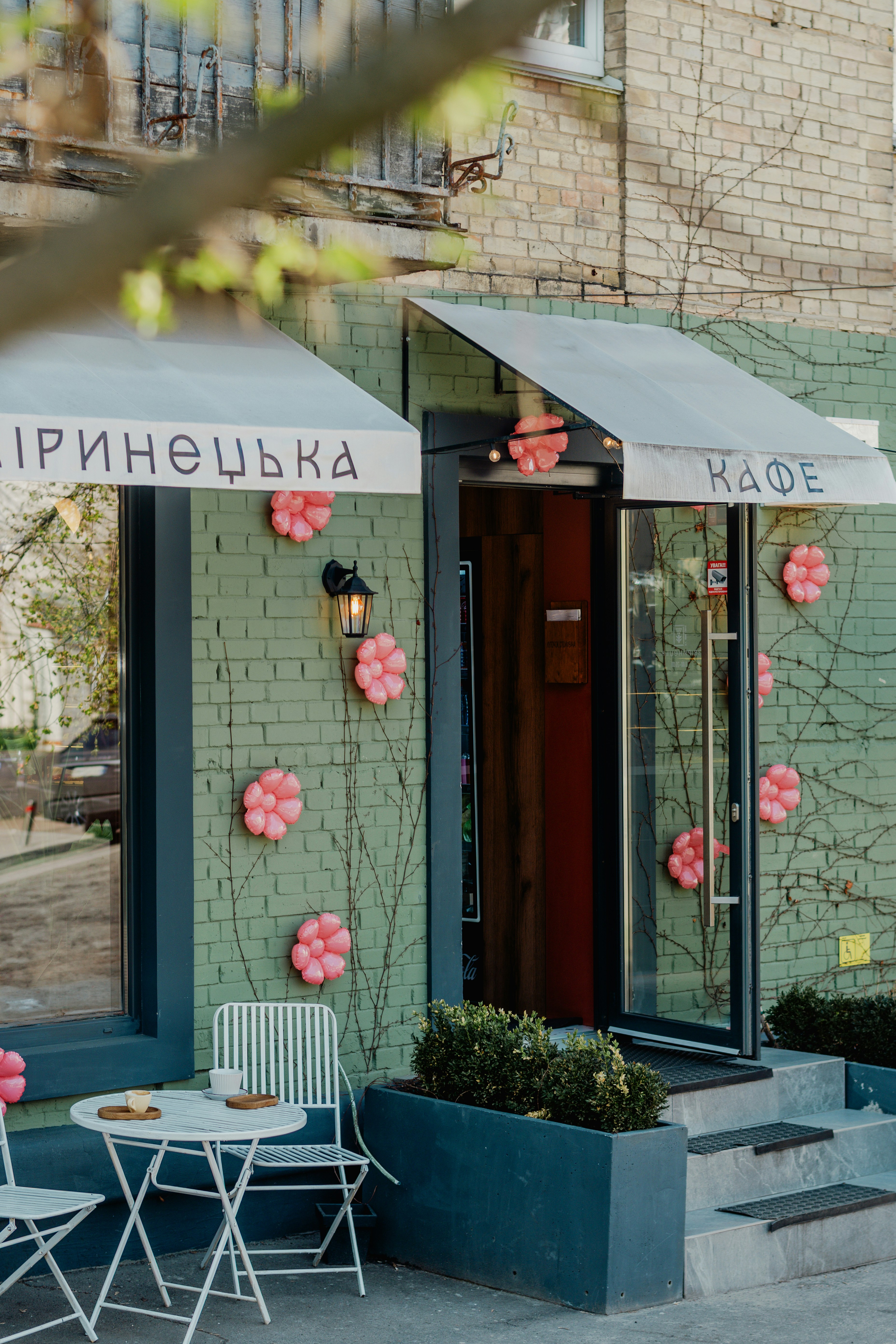 Pastel Café Doors: A Floral Welcome on a Green Facade