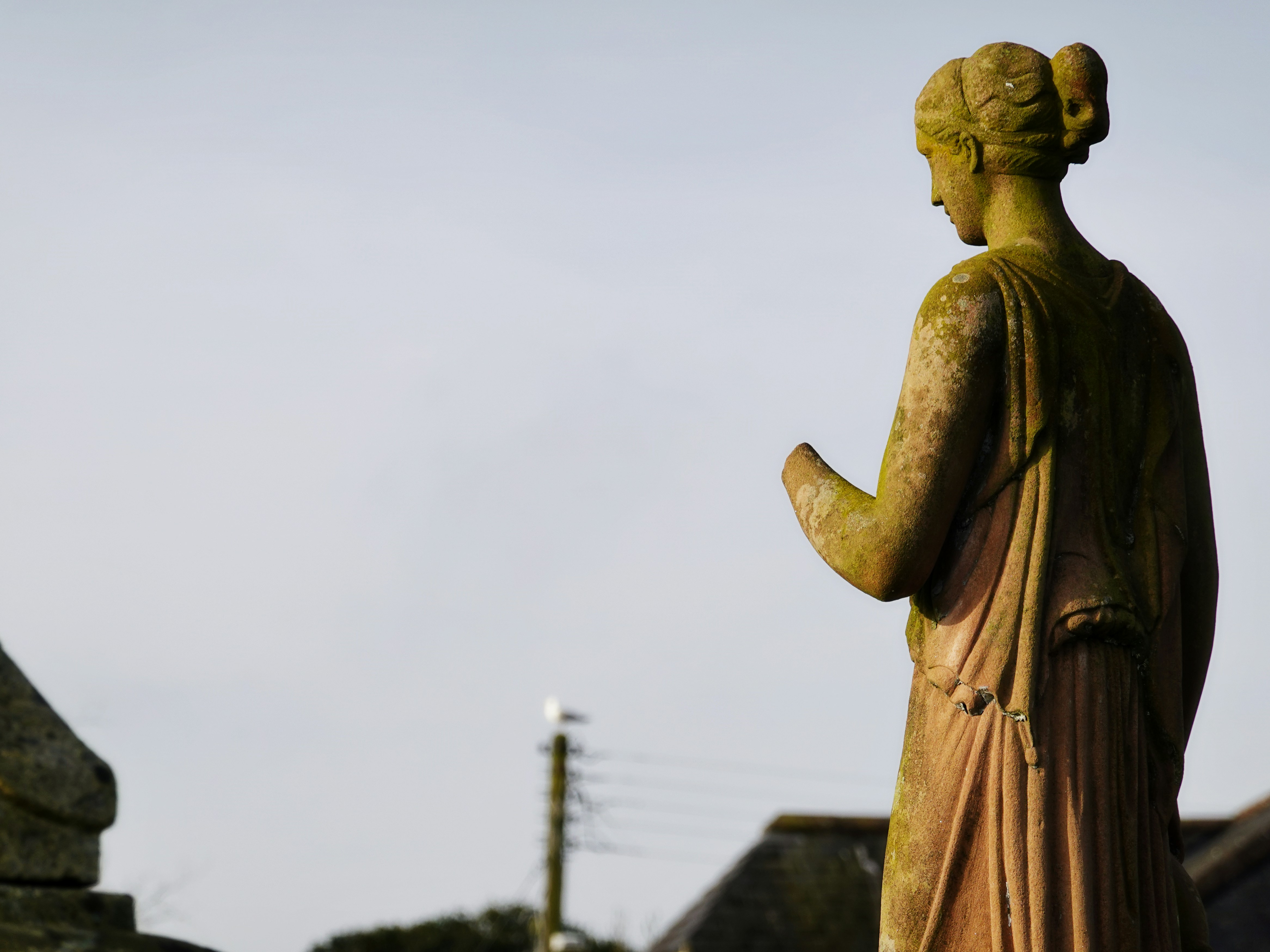 Silent Guardian: A Weathered Statue Beneath An Open Sky