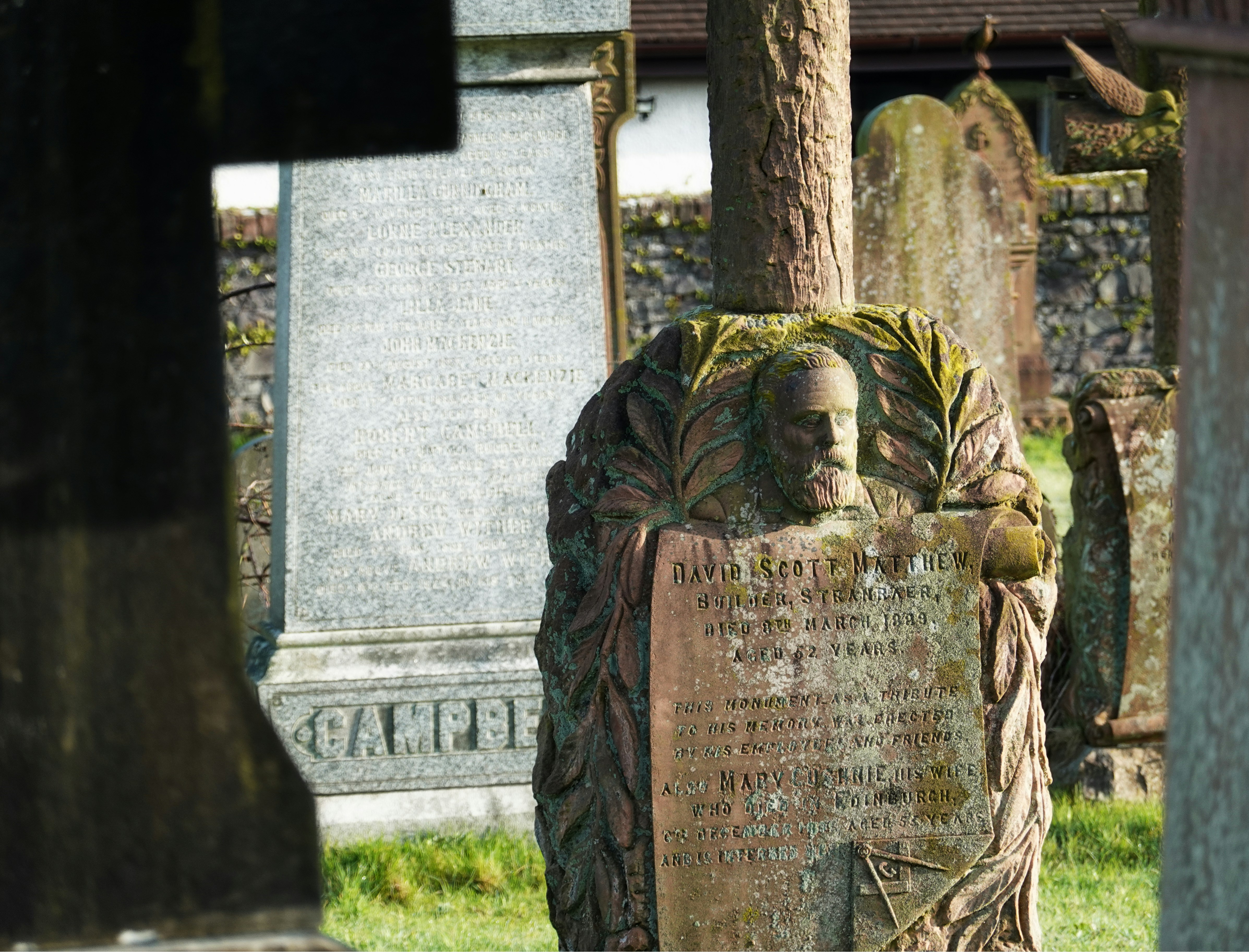 Carved Guardian: A Gravestone with Draped Leaves and Portrait