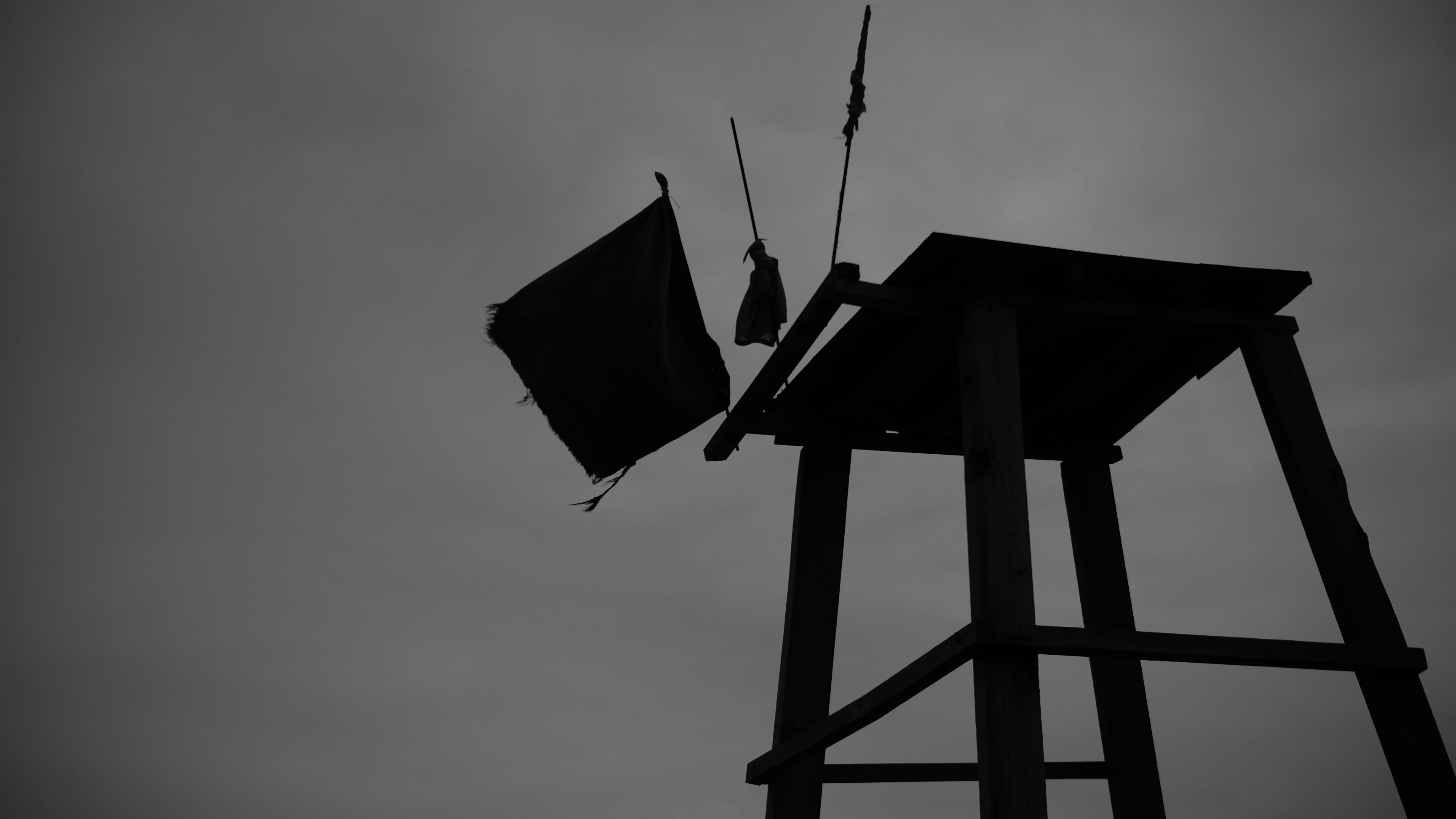 Crumpled Flag Over a Weathered Gallows Tower at Dusk