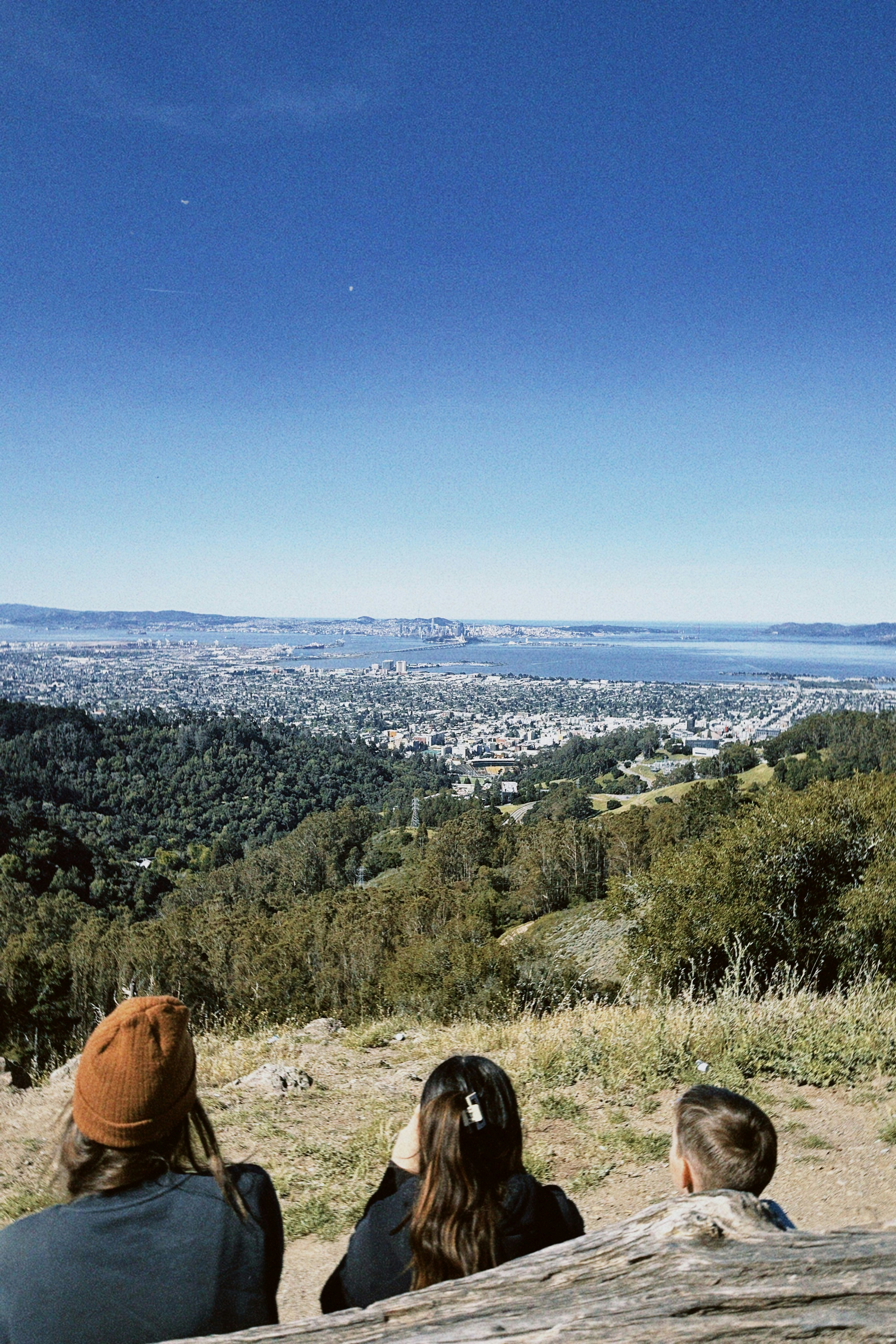 Three friends overlook a sunlit valley from a grassy overlook