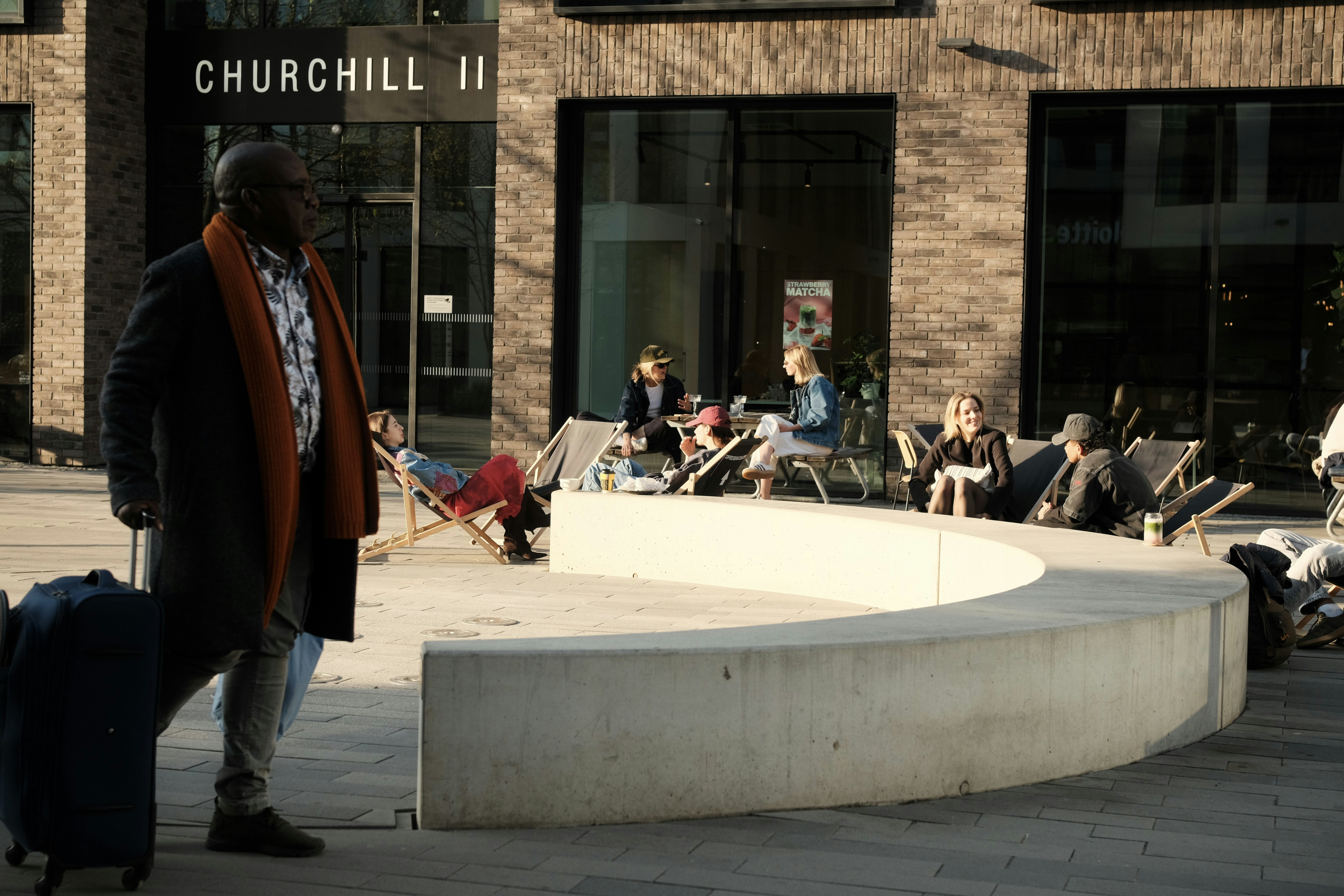 Striding Traveler with Orange Scarf Near a Circular Bench