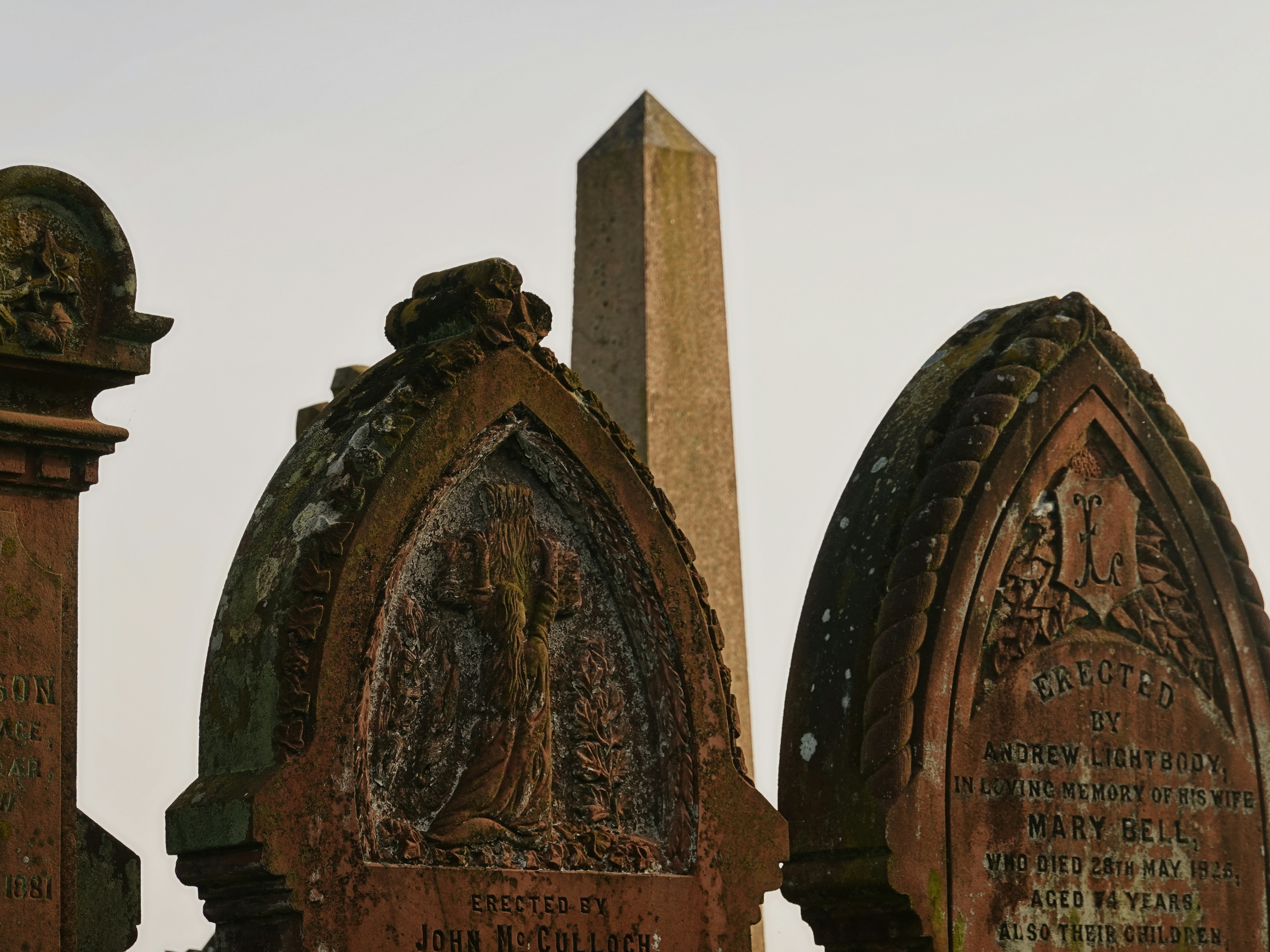 Weathered stone guardians: carved memorials against a pale sky
