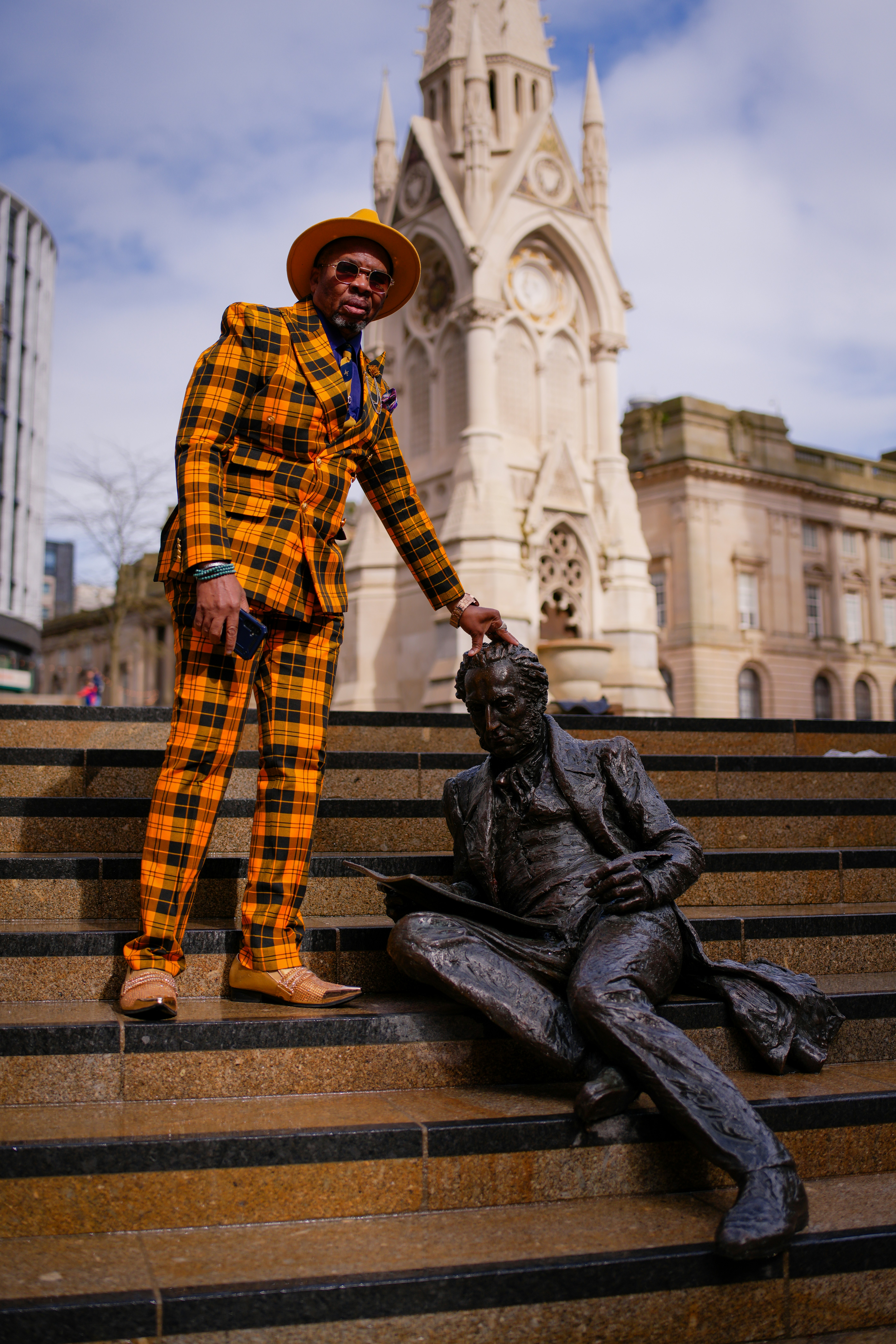 Orange Suit, Blue Tie: A Gentleman’s Stance with the Statue