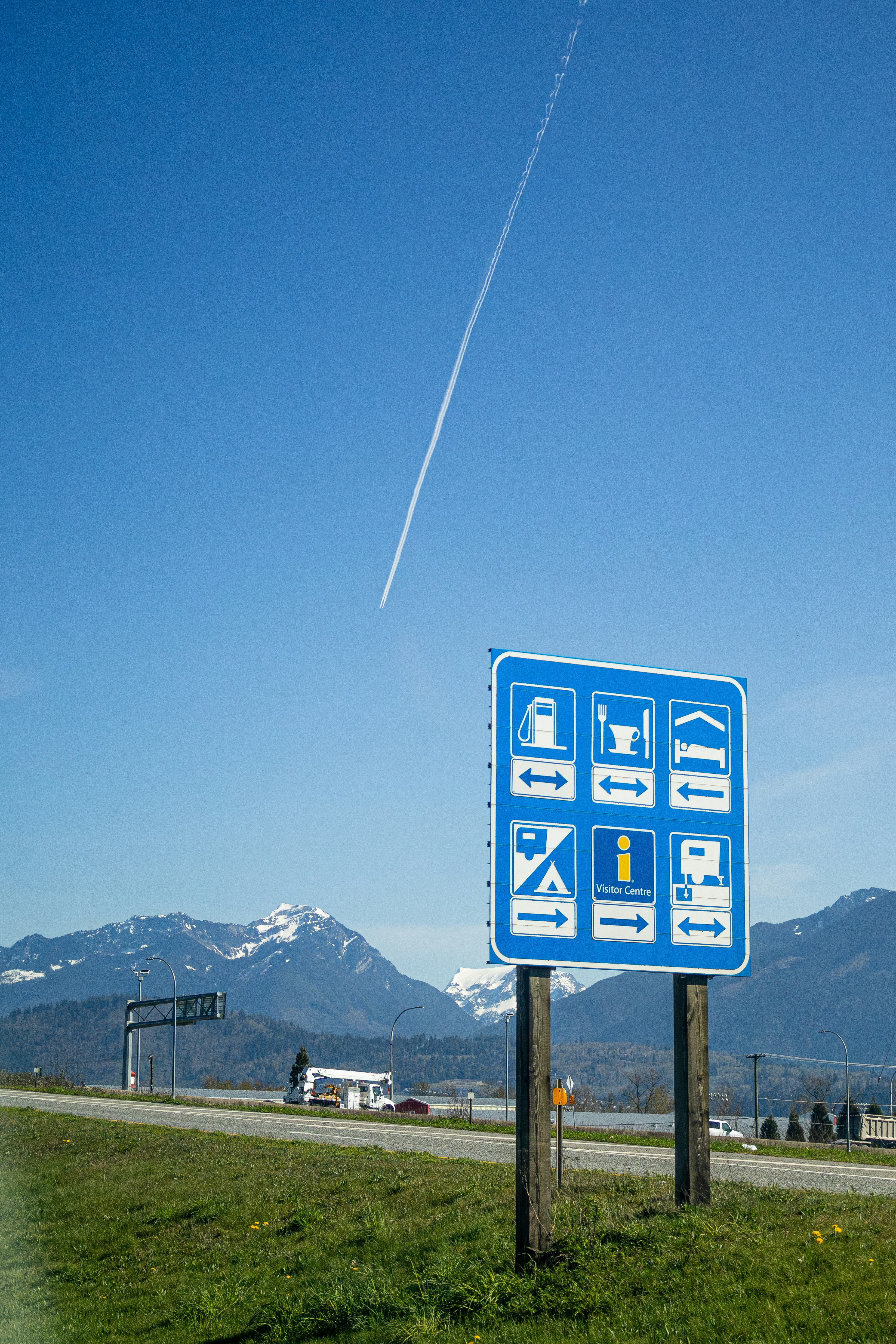 Blue Signpost between Open Sky and Snowy Peaks
