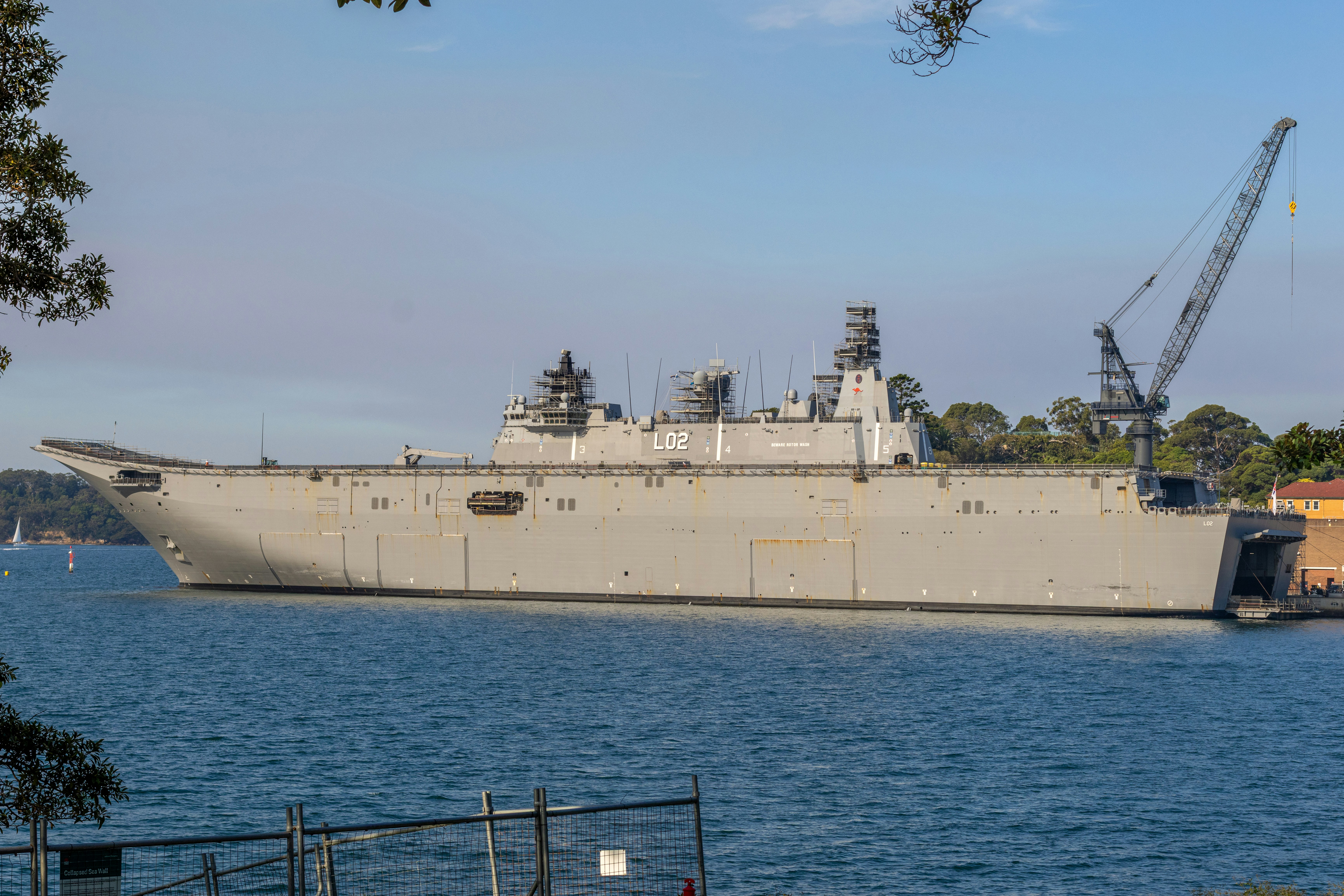 Docked warship at harbor: a quiet industrial silhouette against blue water