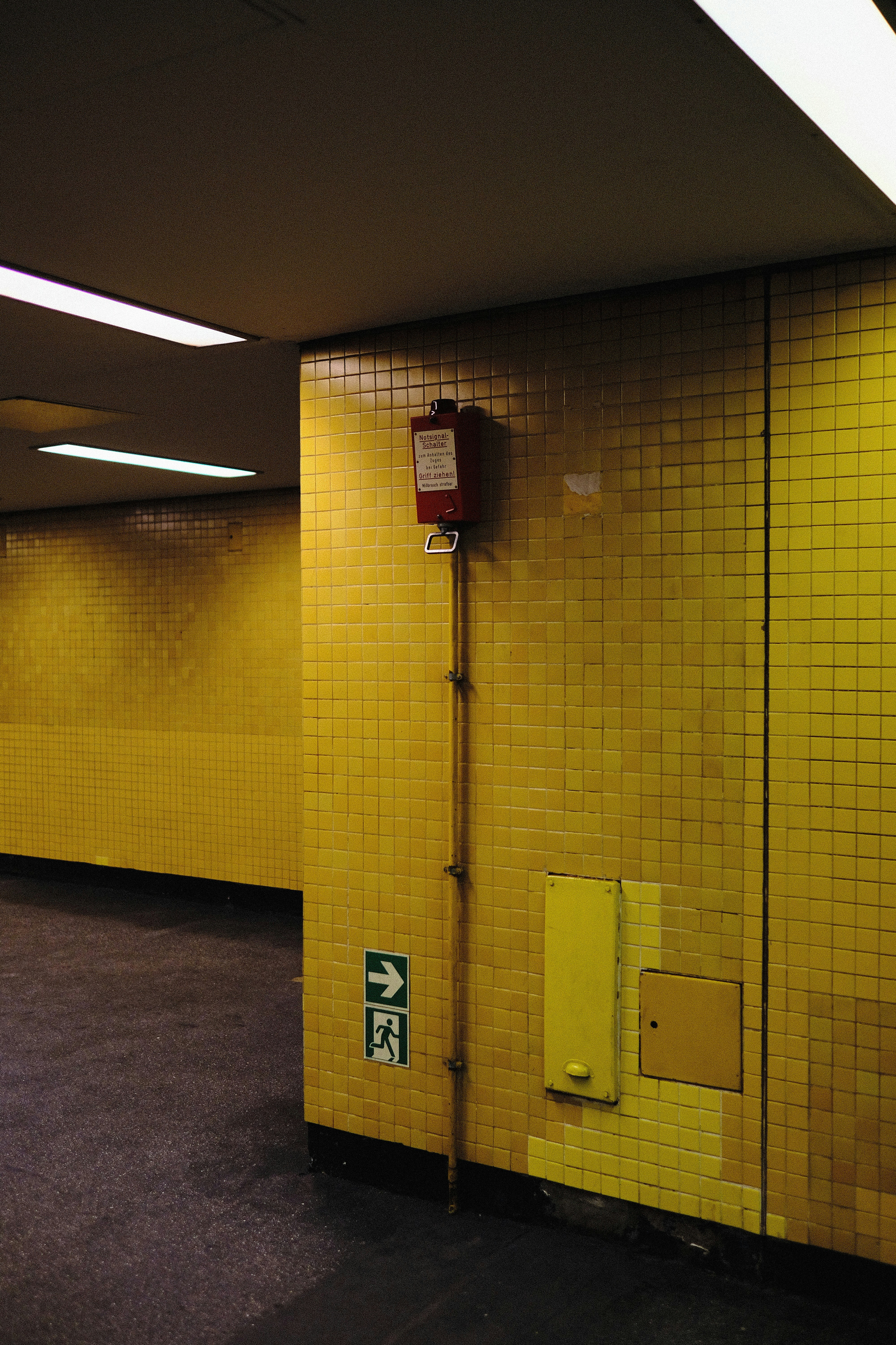 Yellow-tiled Corridor with Safety Signage and Fire Equipment