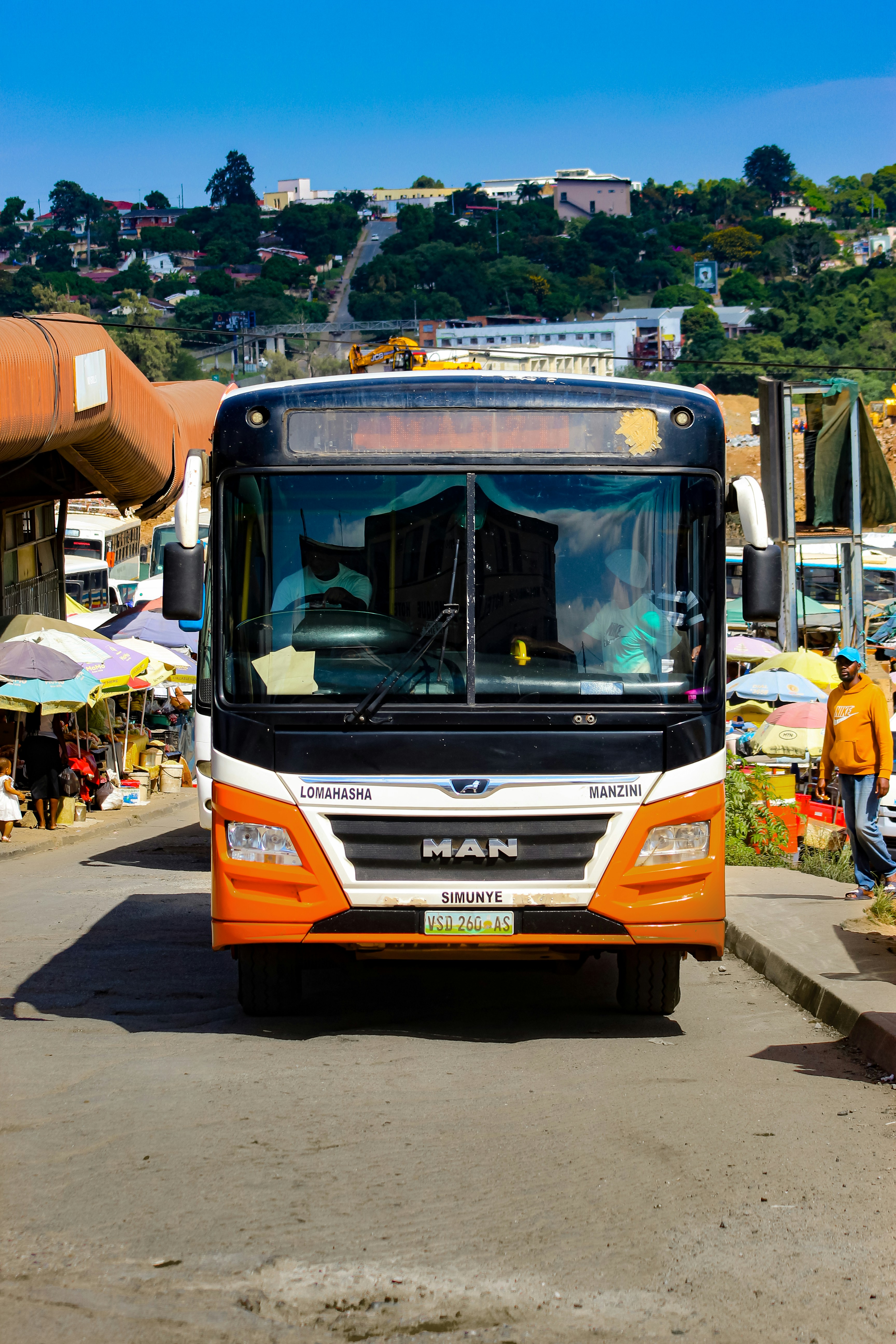 Front and Center: The Orange MAN Bus in a Bustling Market Corridor